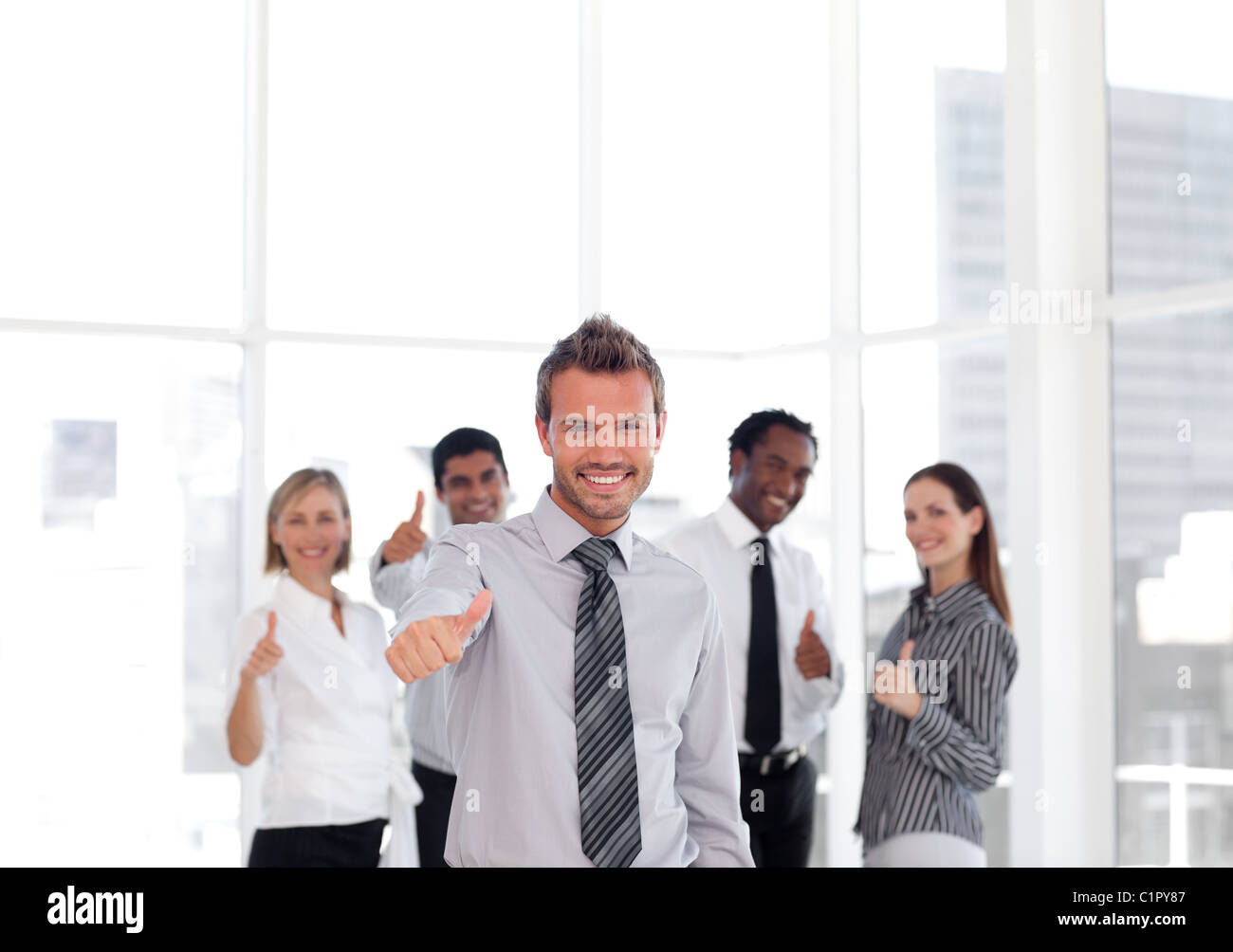 Self-assured business manager standing at the camera with his team ...