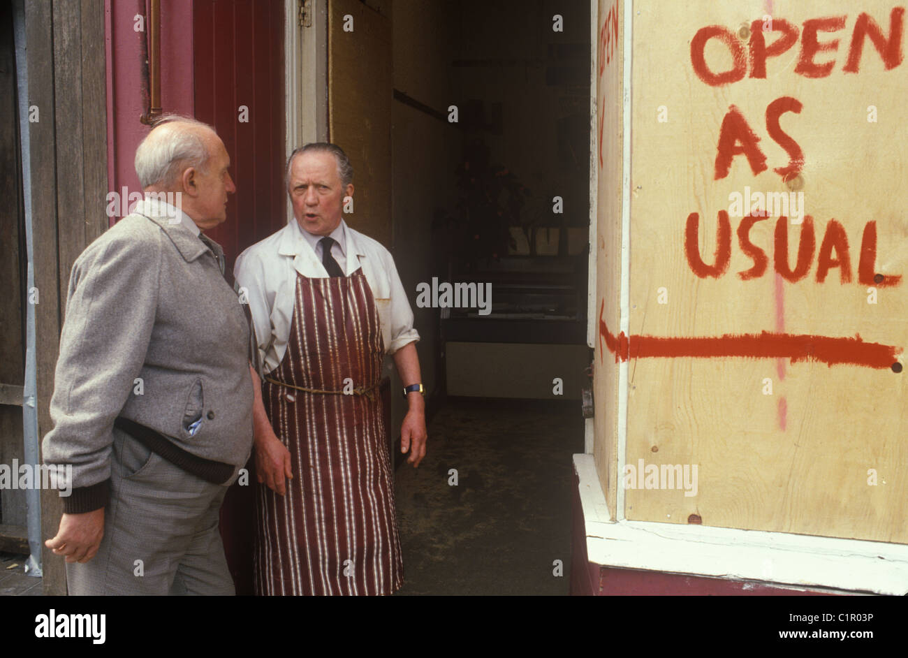 Toxteth Riot 1980s UK. A butcher in his butchers apron stands outside ...