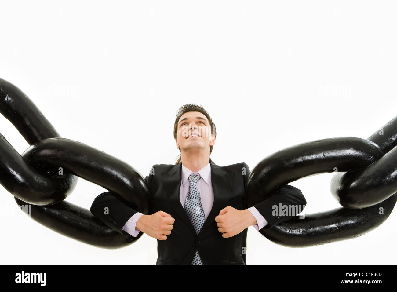 Portrait of powerful businessman holding two sections of huge chain by ...