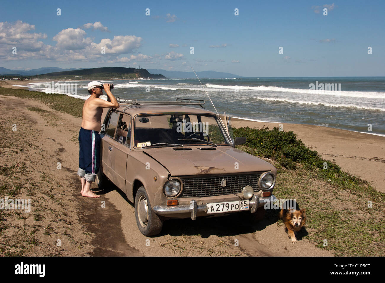 A man stands by his car by the beach in Okhotsk, Sakhalin, Russia ...