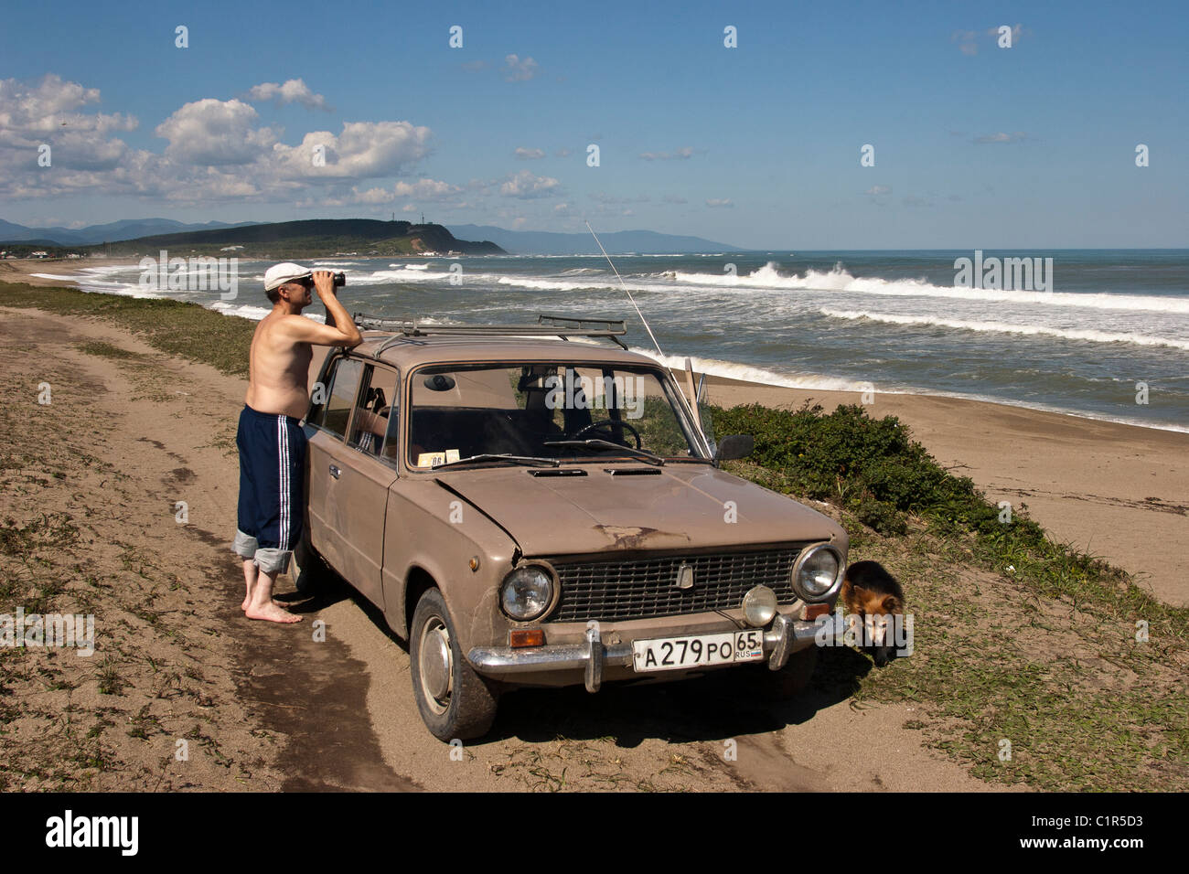A man stands by his car by the beach in Okhotsk, Sakhalin, Russia ...