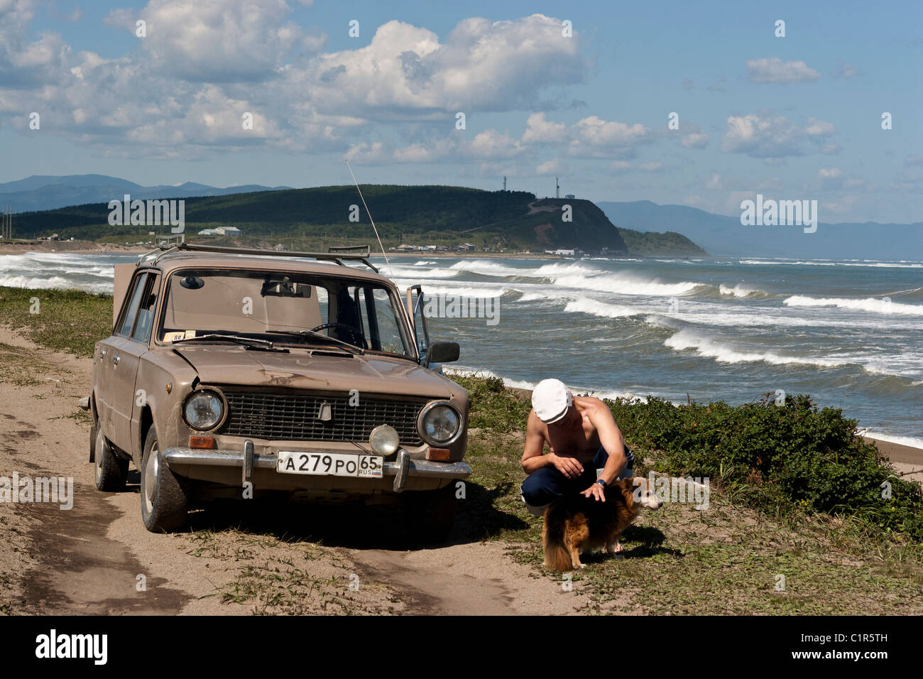 A man stands by his car by the beach in Okhotsk, Sakhalin, Russia ...