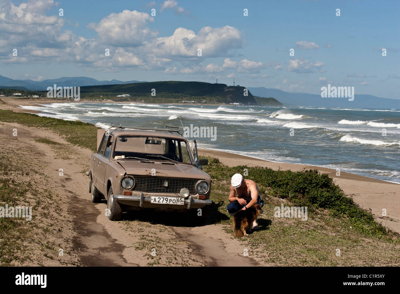 A man stands by his car by the beach in Okhotsk, Sakhalin, Russia ...