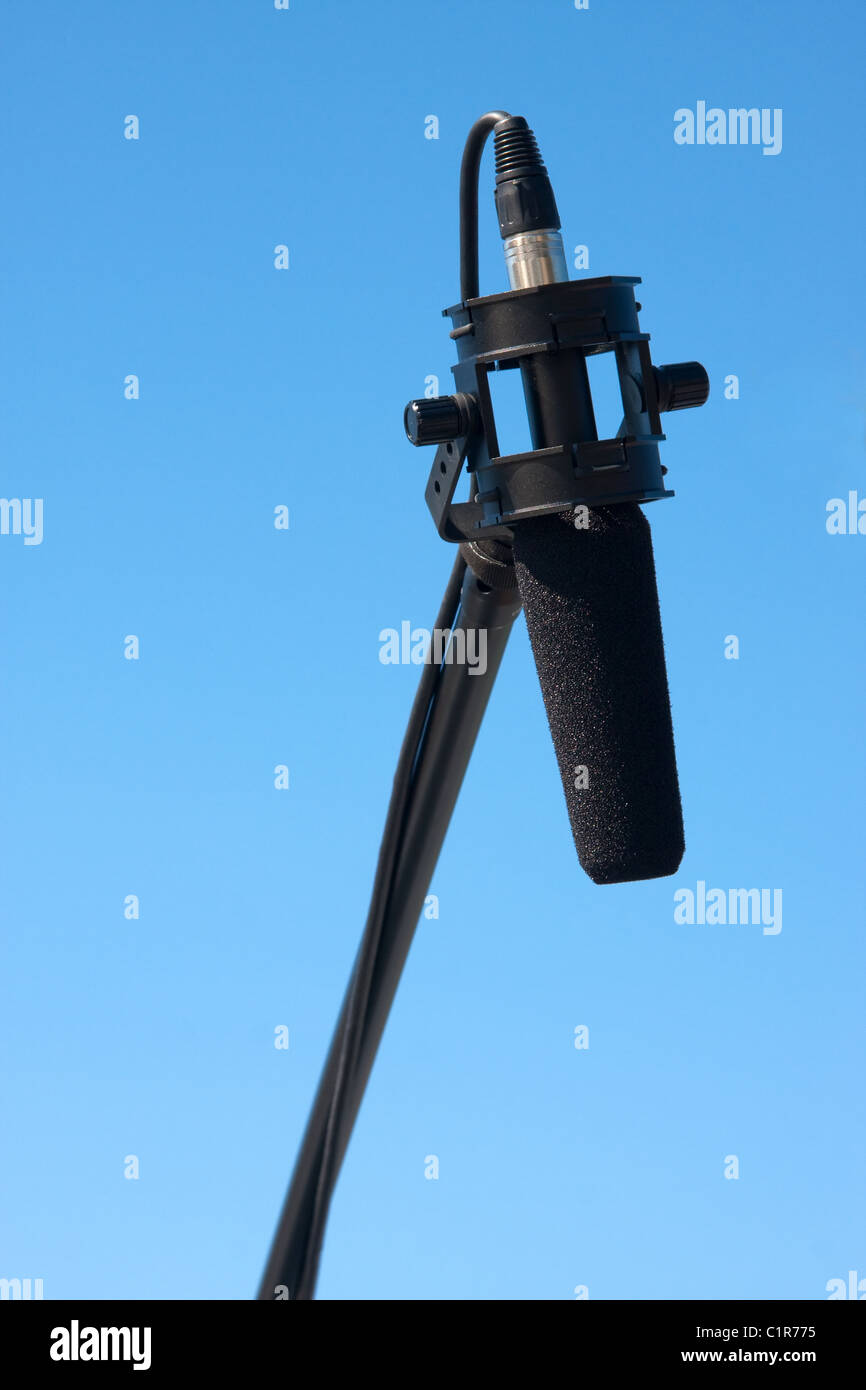 Boom mike with foam windscreen using an xlr plug against a clear blue ...