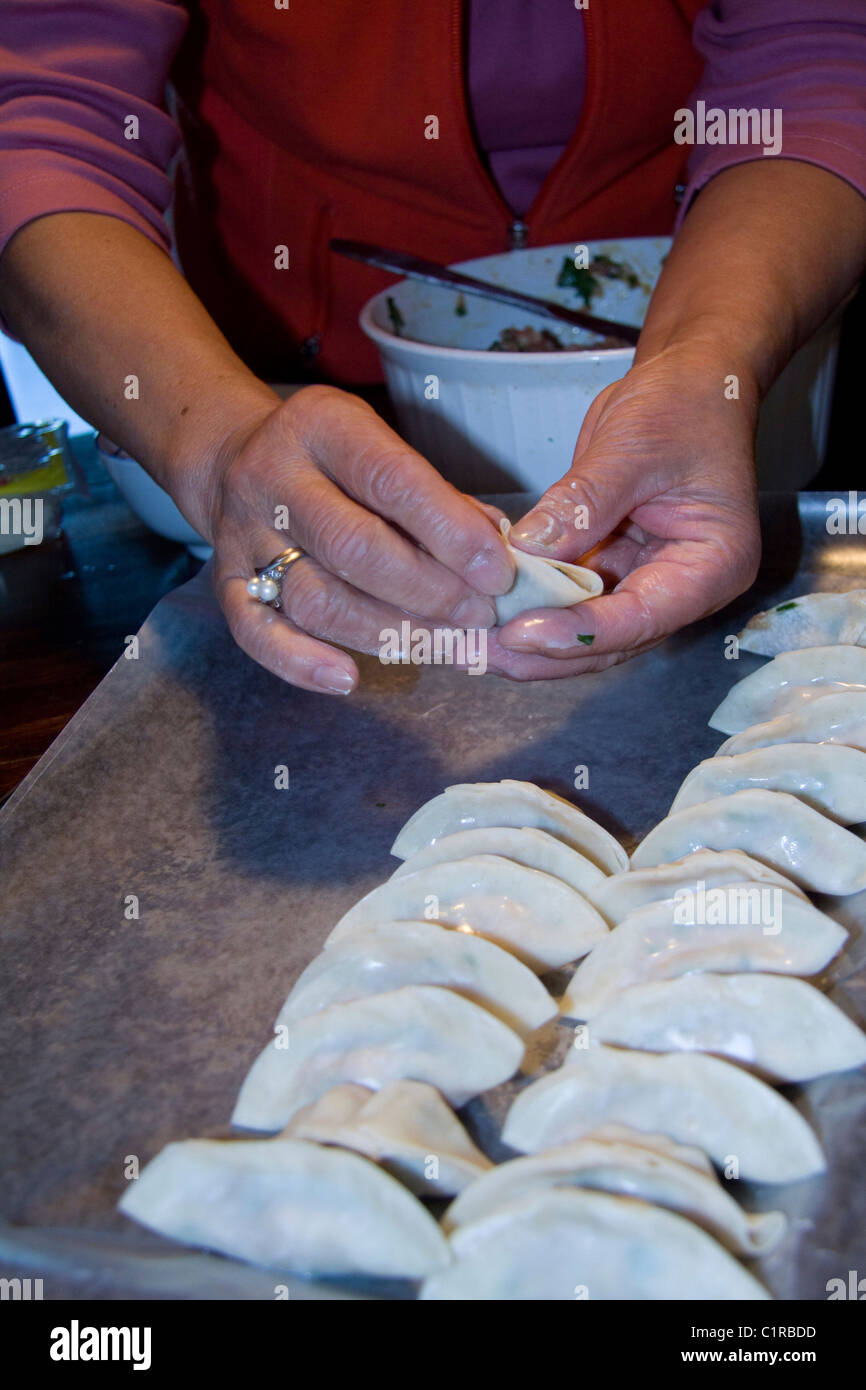 Chinese cook demonstrating how to make wor tip, potstickers or pork ...