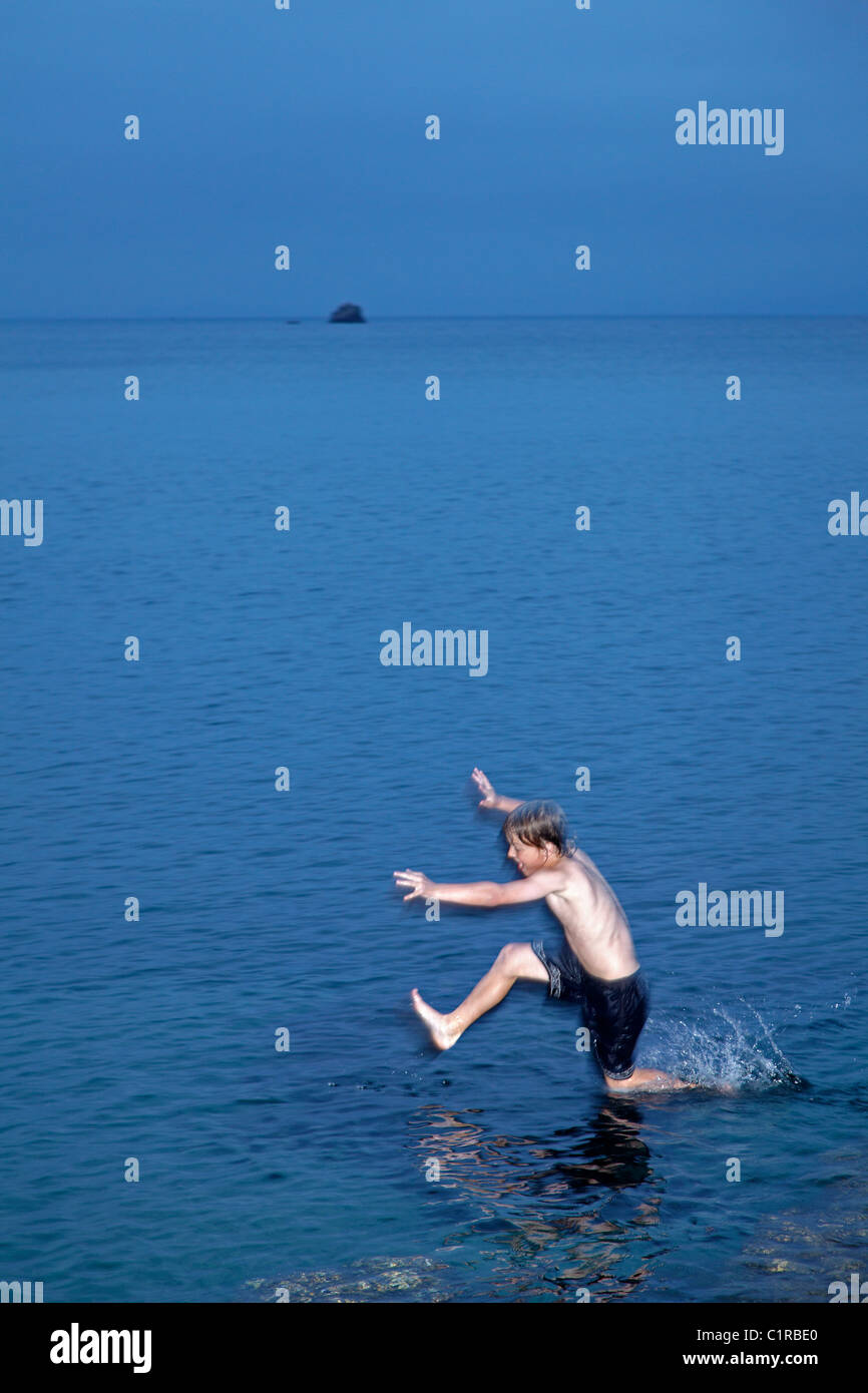 Boy jumping off rocks at Parakerake Bay at dusk, Whatuwhiwhi, Doubtless ...
