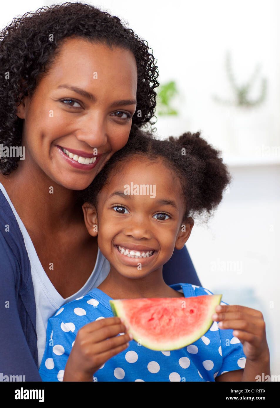 Smiling mother and her daughter eating fruit Stock Photo - Alamy