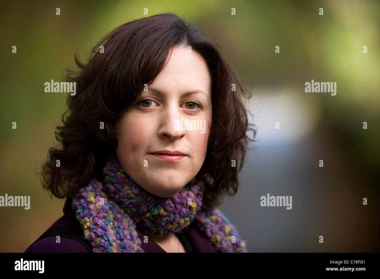 A woman looking slightly stern in the center of the frame looking at ...