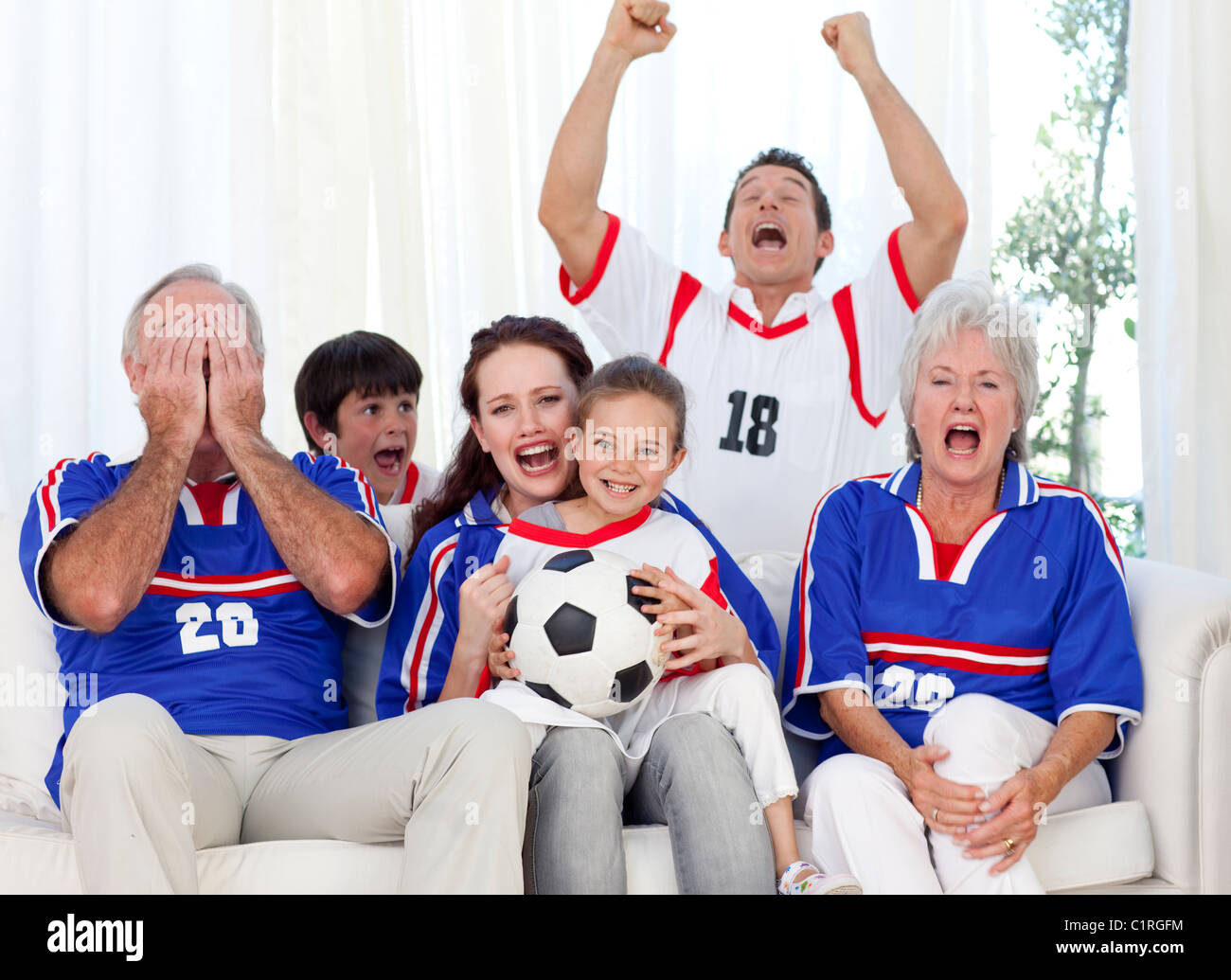 Family watching a football match in television Stock Photo - Alamy
