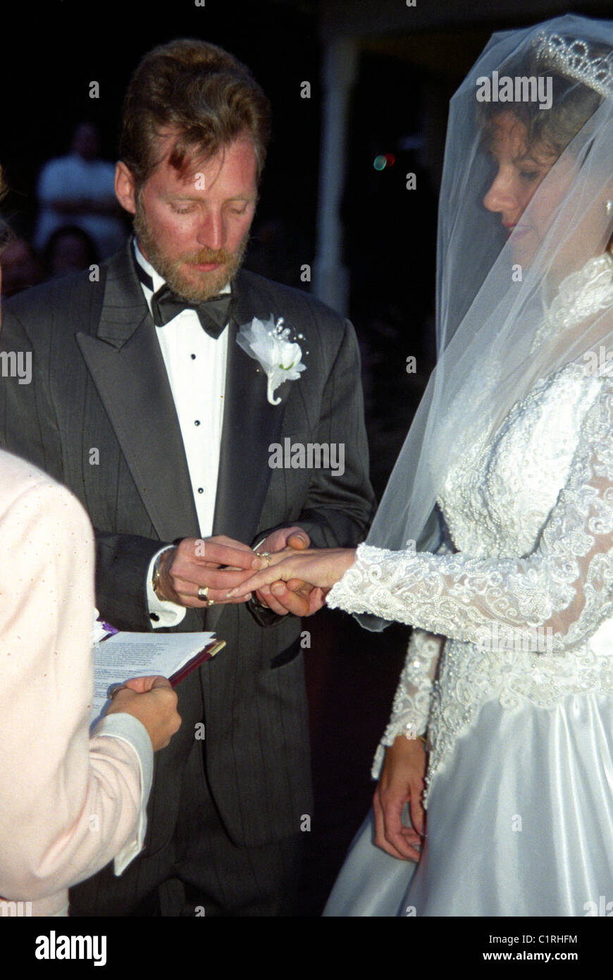 couple getting married with groom placing the ring on the bride's ...