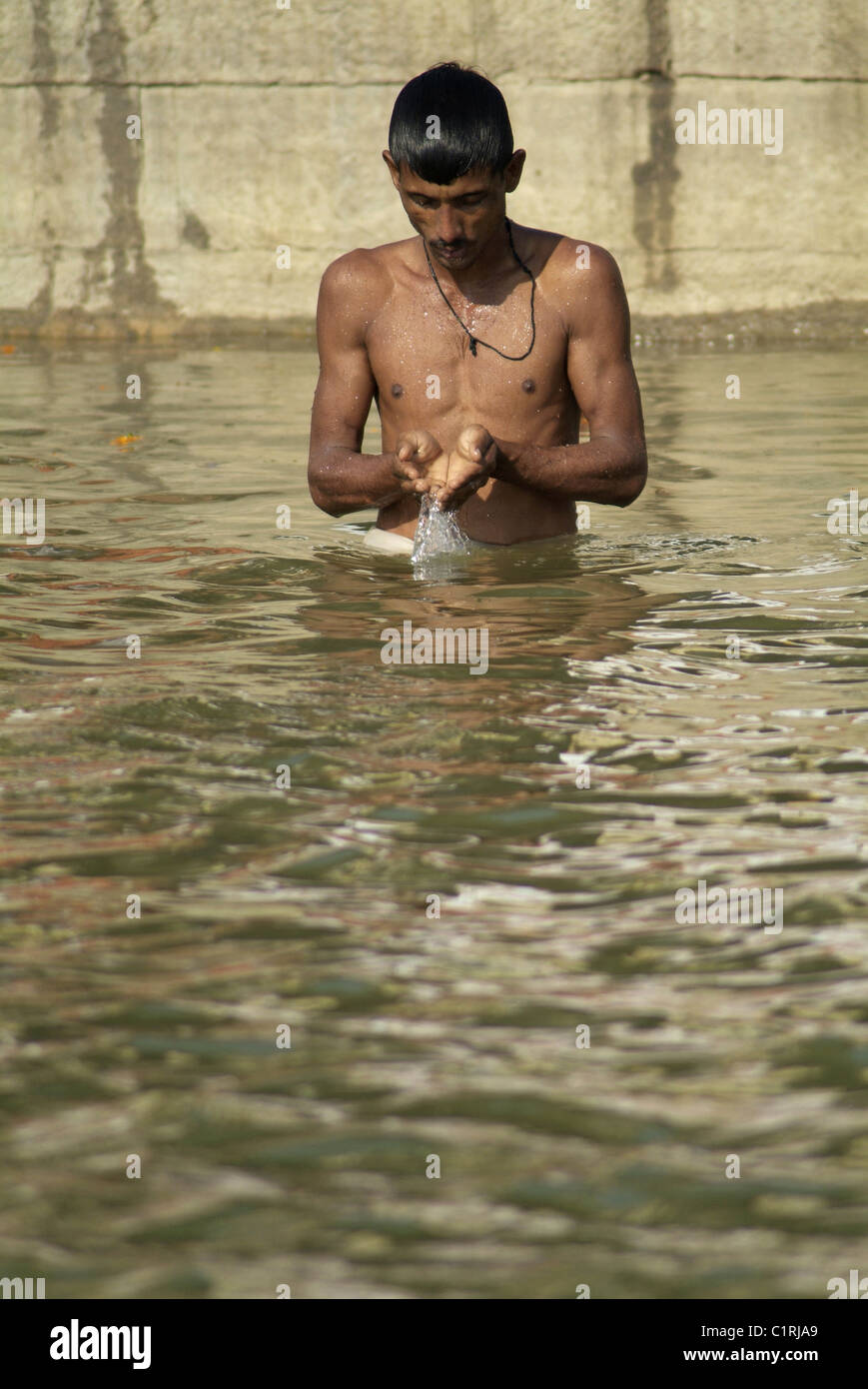 Hindu man praying in the holy waters of the Ganges River in Varanasi ...
