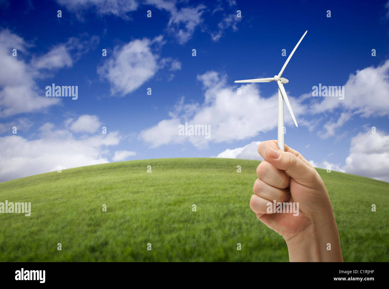 Male Fist Holding Wind Turbine Outside with Grass Field, Sky and Clouds ...