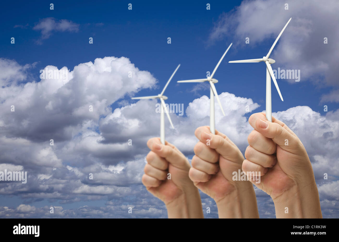 Male Fists Holding Three Wind Turbines Outside with Clouds and Sky ...