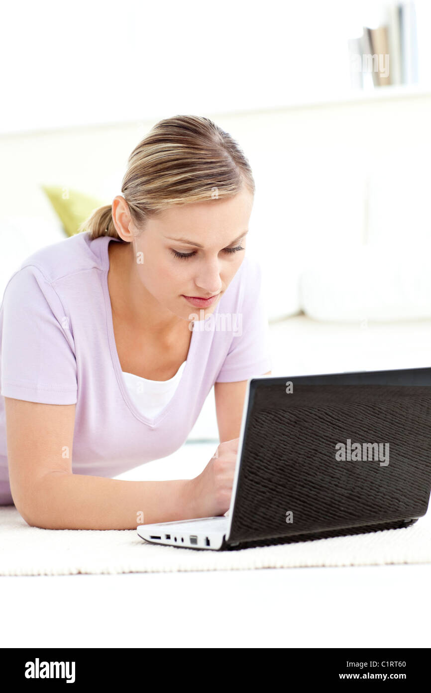Concentrated woman using her computer lying on the floor Stock Photo ...