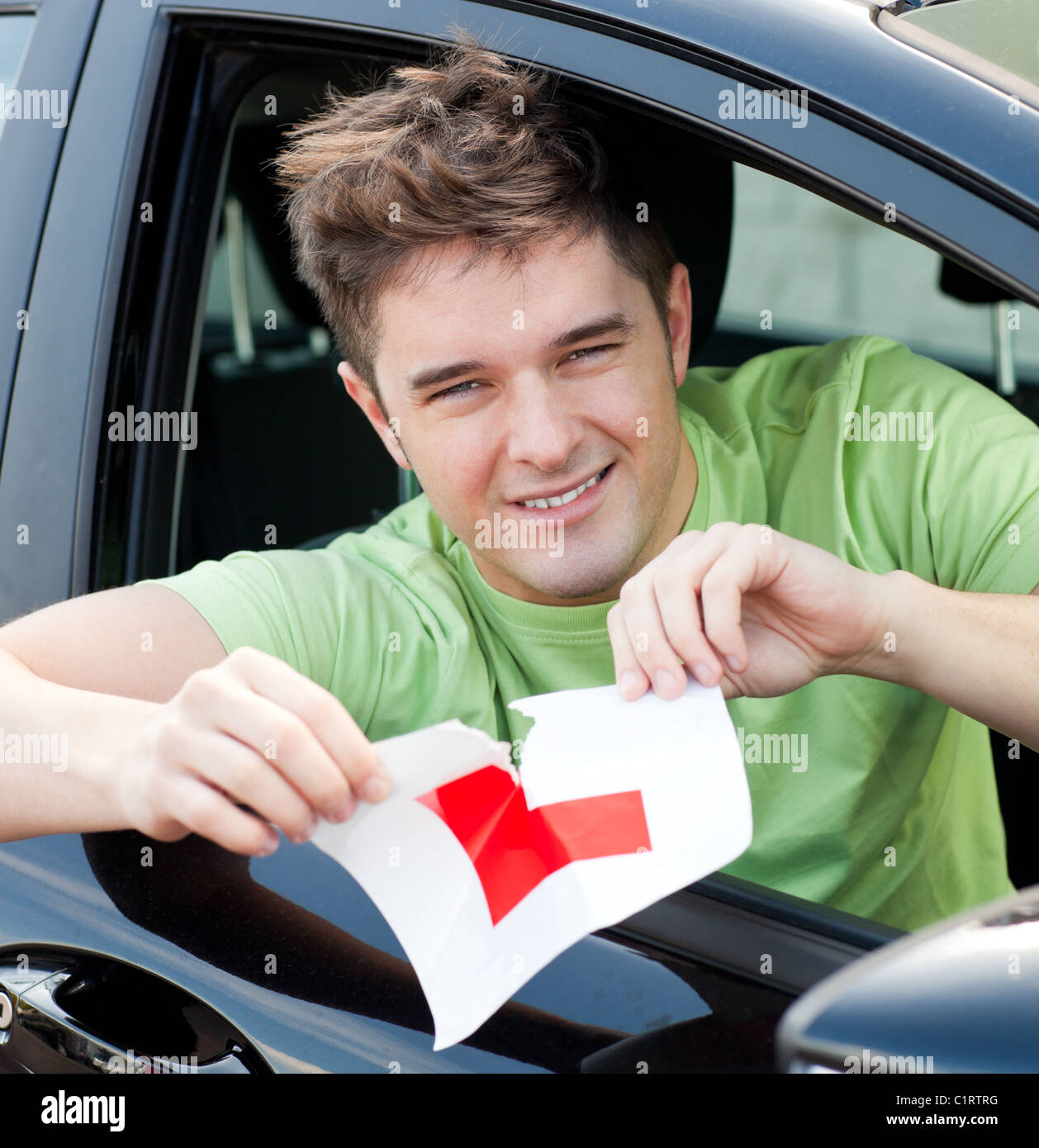 Happy young male driver tearing up his L sign Stock Photo - Alamy
