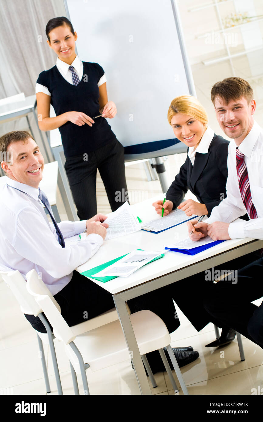 Portrait of executive business group sitting at table and smiling at ...