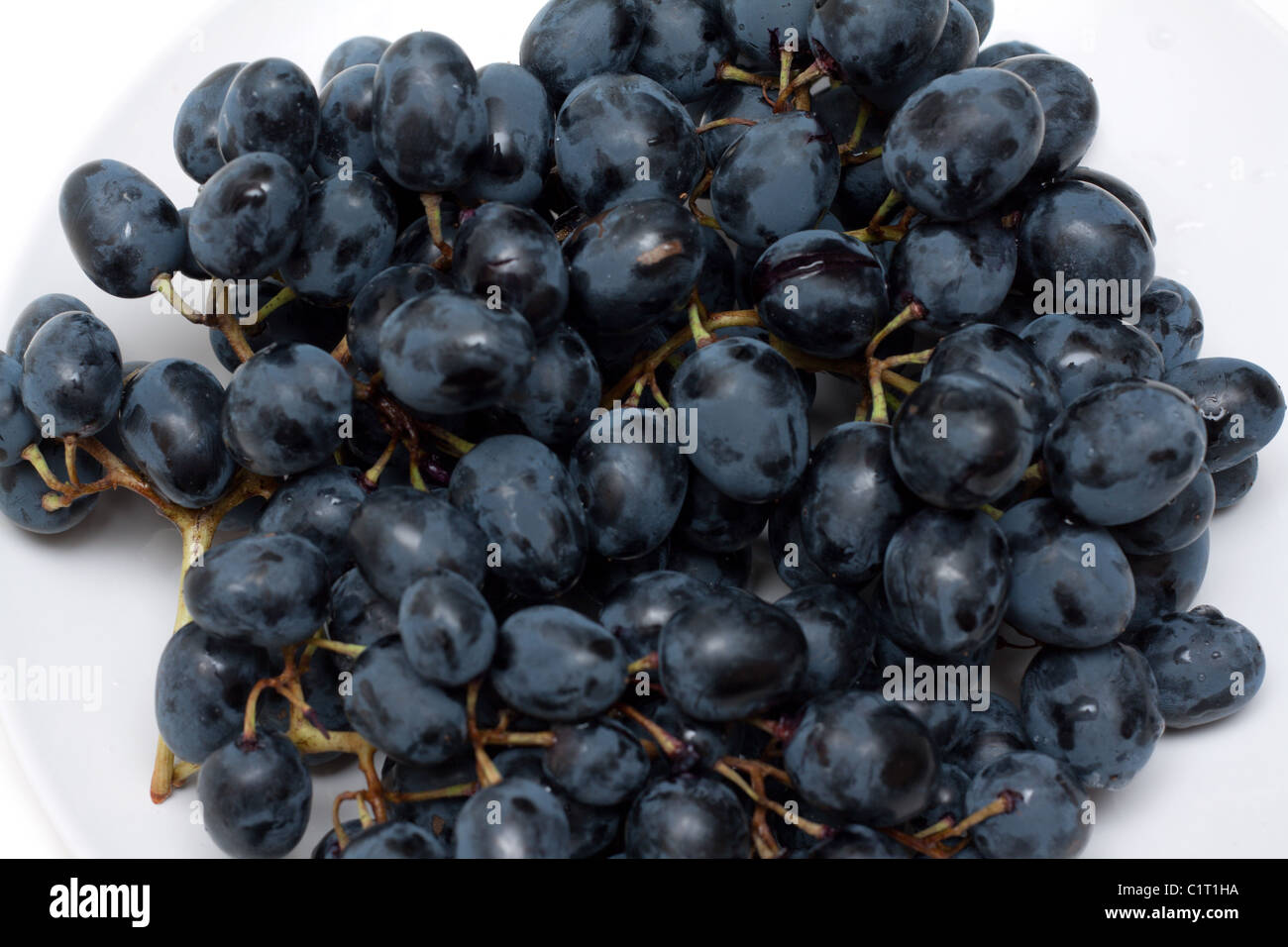 Blue grape put on plate on white background Stock Photo - Alamy