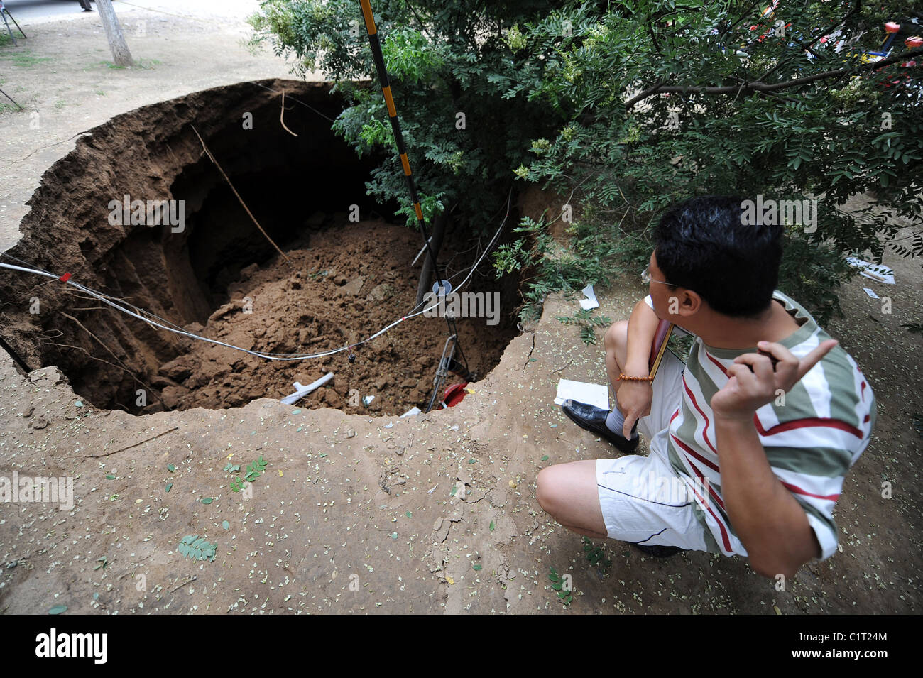 Workers try to salvage a huge tree which has disappeared into a hole ...
