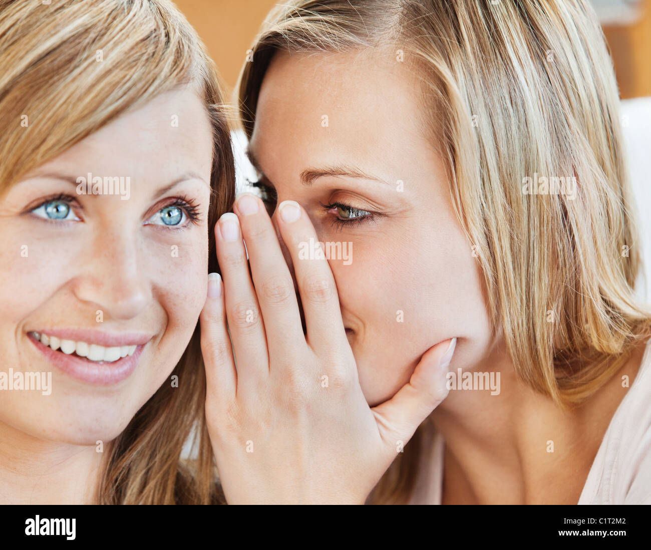 Portrait of two female friends telling secrets Stock Photo - Alamy