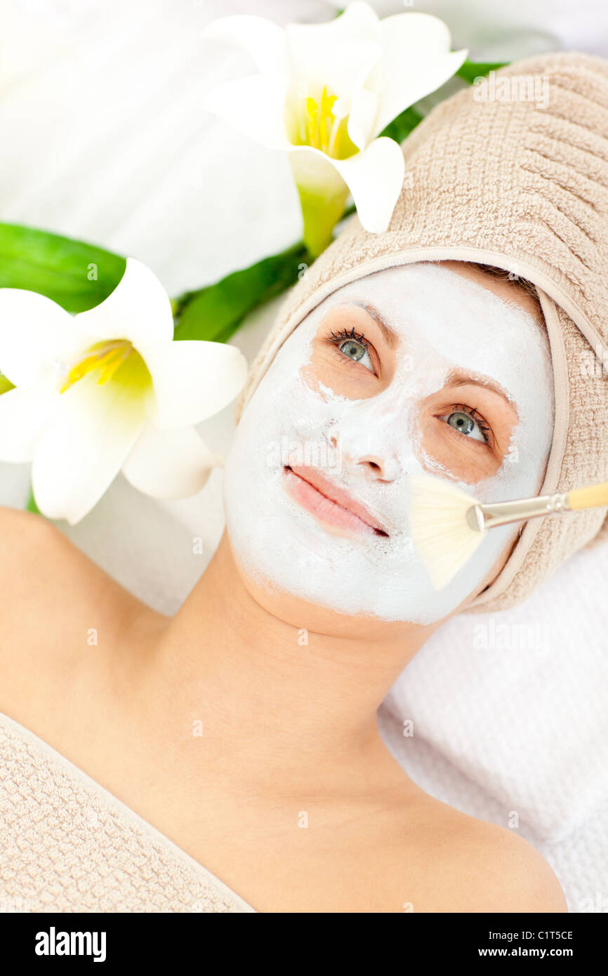 Captivating young woman receiving white cream on her face Stock Photo ...