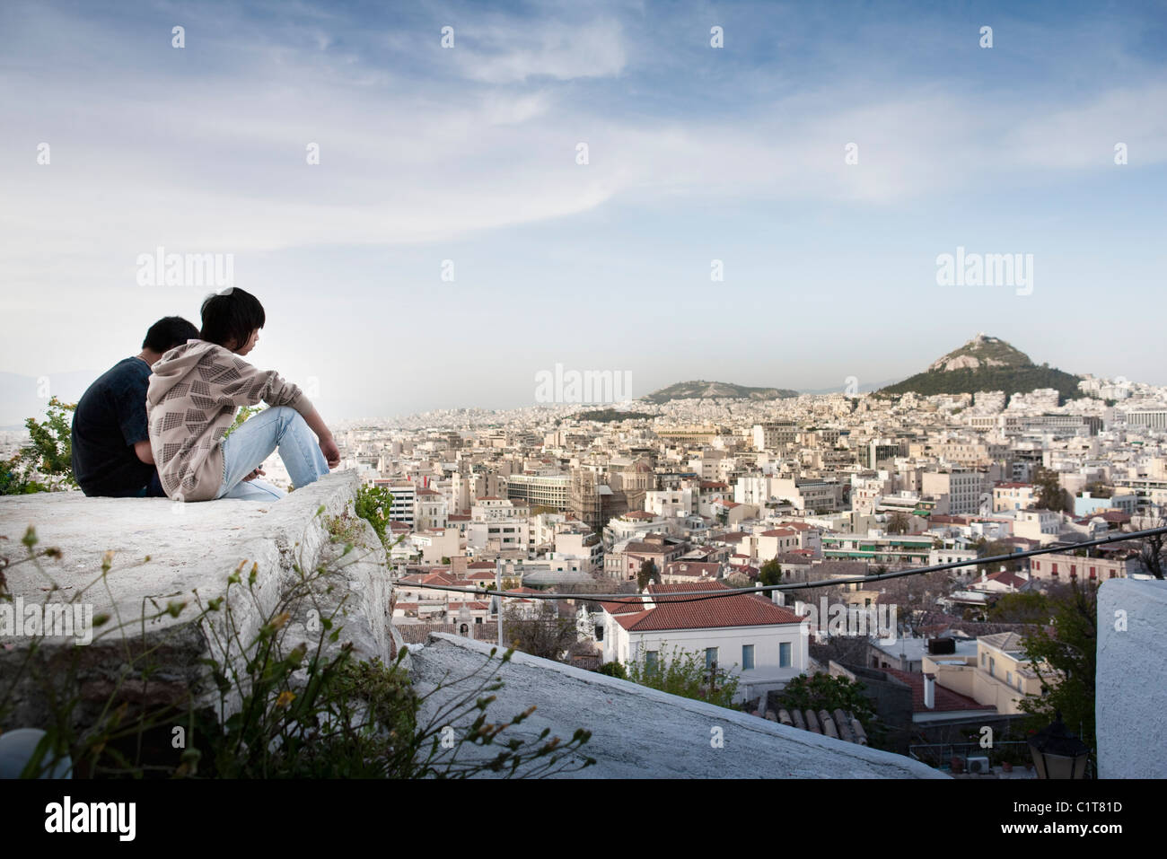Tourists sitting on rock overlooking Athens, Greece and Mount ...