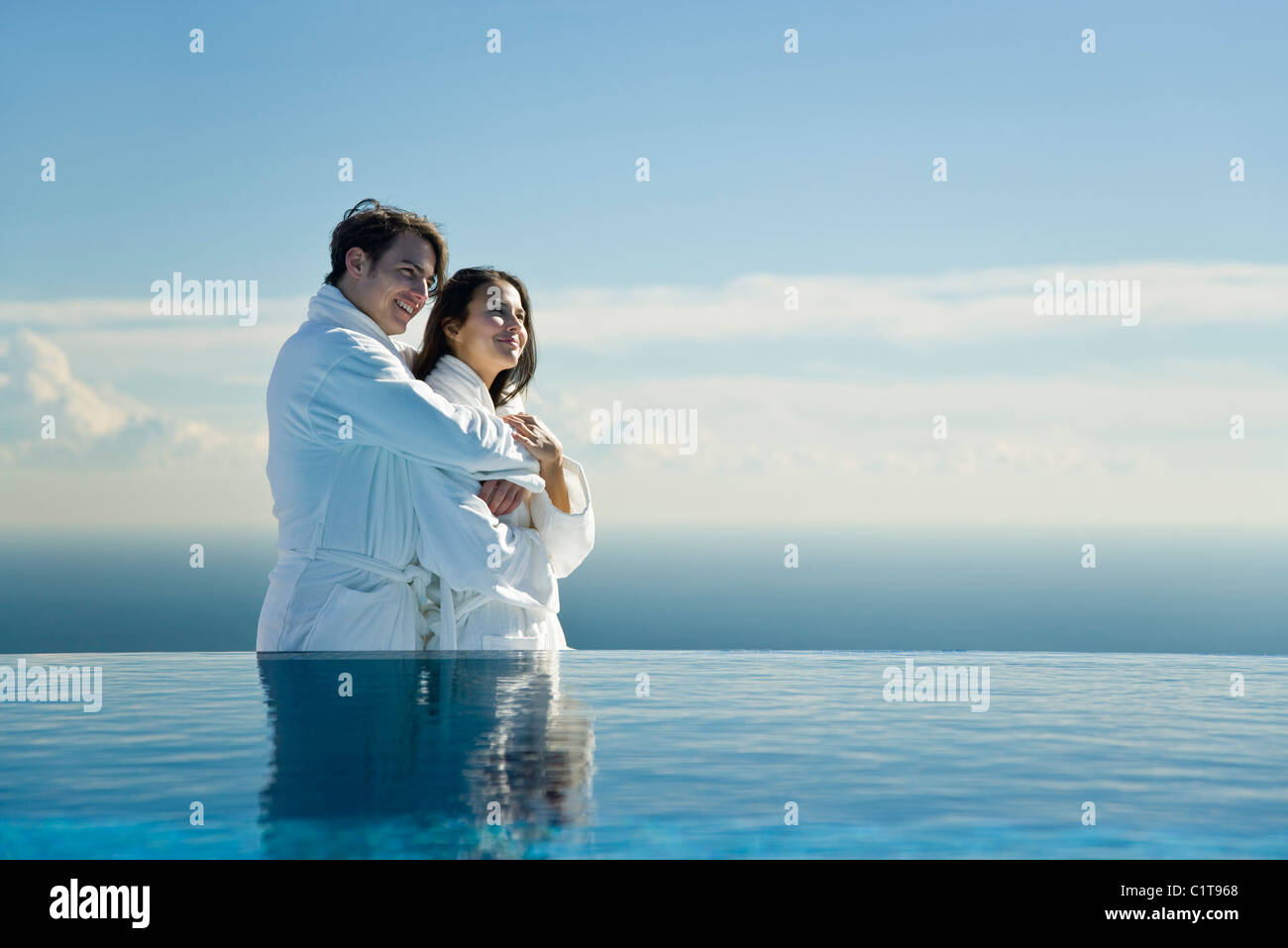 Couple embracing at edge of infinity pool, both wearing bathrobes Stock ...