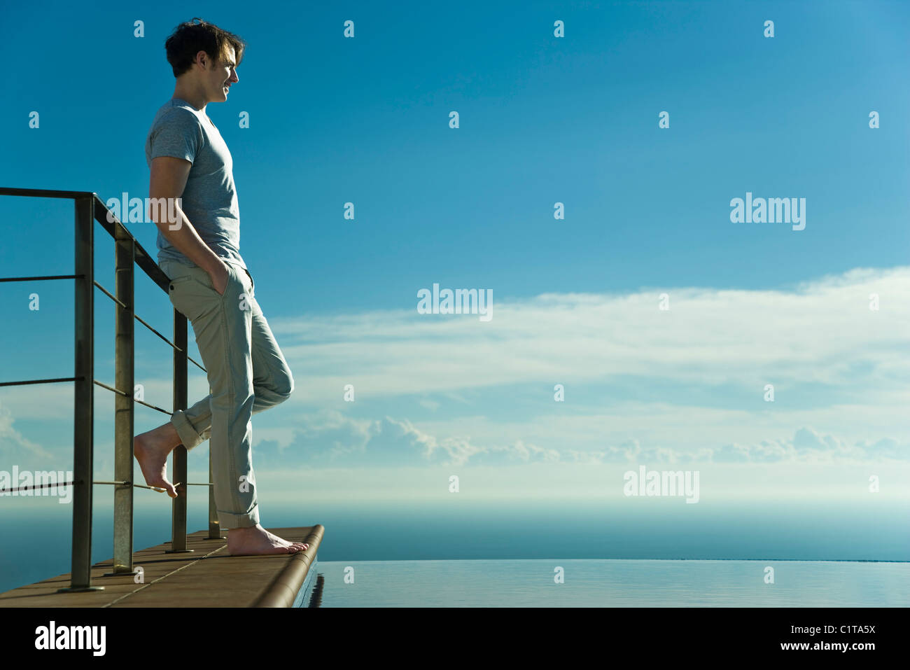 Man leaning against railing, looking at view Stock Photo - Alamy