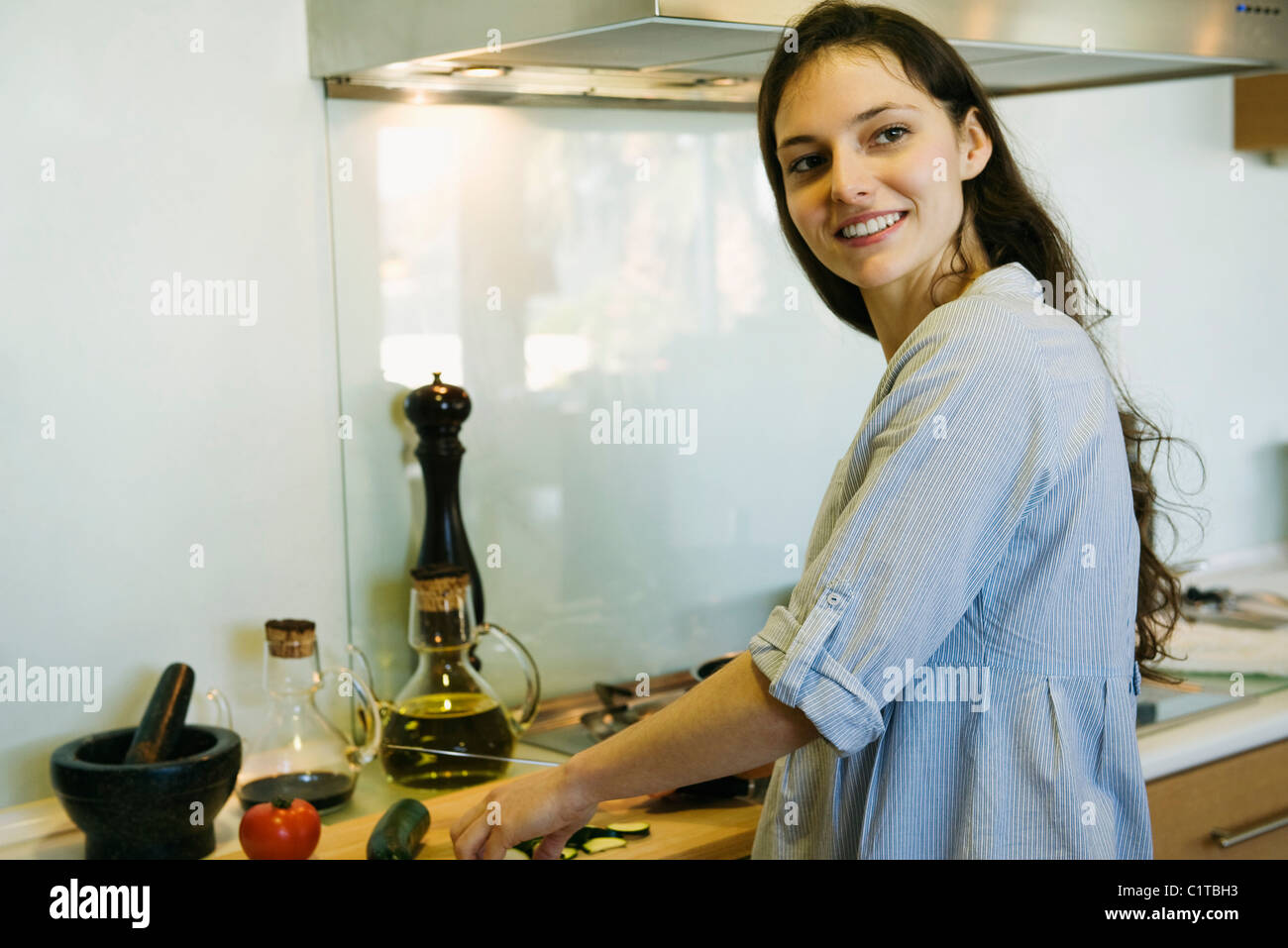 Woman cooking, smiling over shoulder, portrait Stock Photo - Alamy