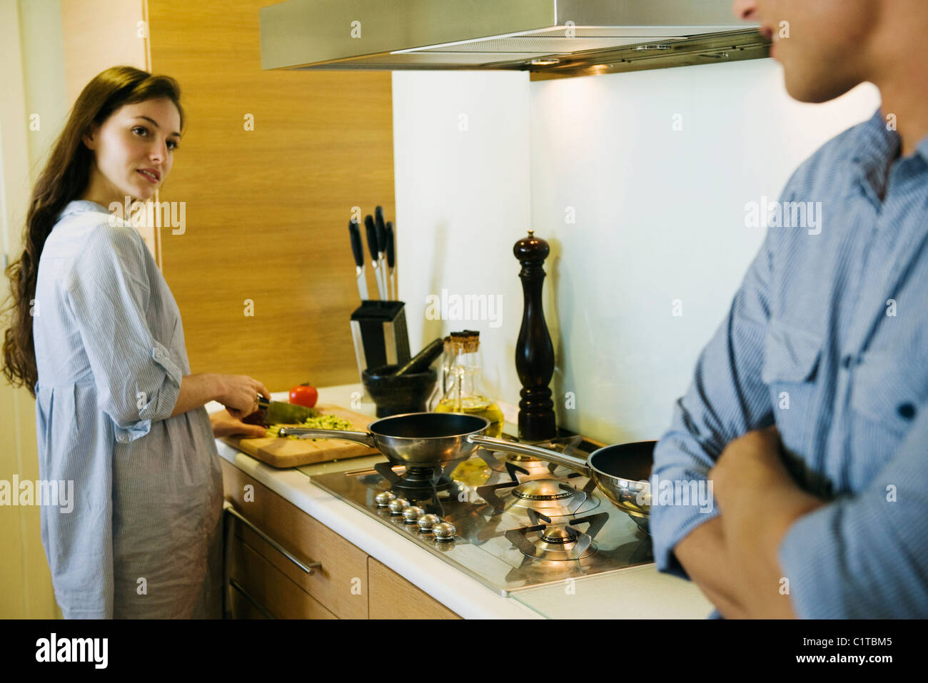 Couple talking together in kitchen as woman prepares food Stock Photo ...