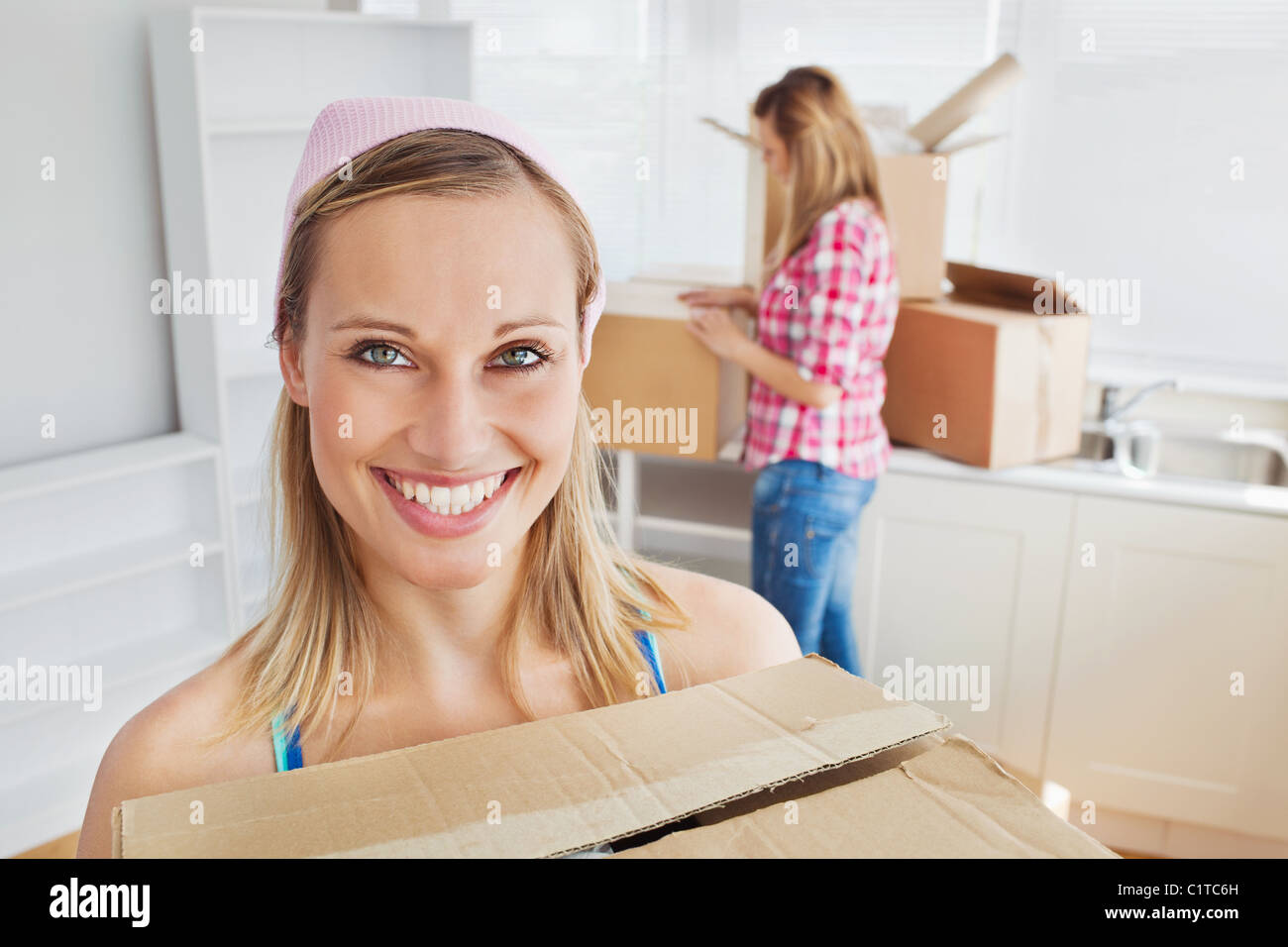 Two positive women carrying boxes at home Stock Photo - Alamy