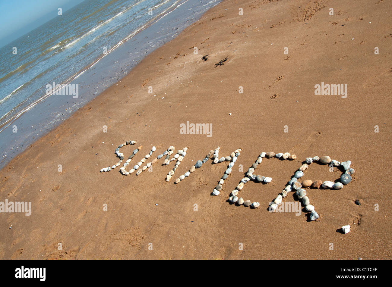 Summer in Stone writing beach sea sand seaside Stock Photo - Alamy