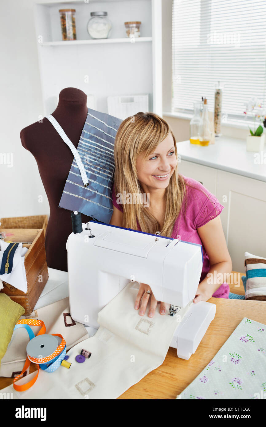 Delighted woman sewing clothes in the kitchen Stock Photo - Alamy