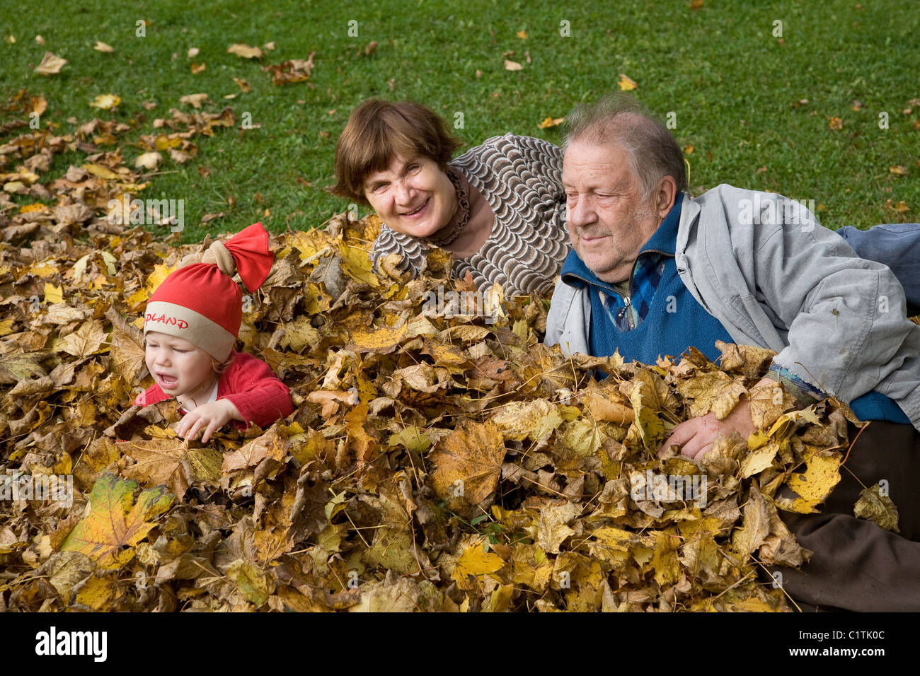 Happy Senior Grandparents with Kid Girl in Fall Leaves Stock Photo - Alamy