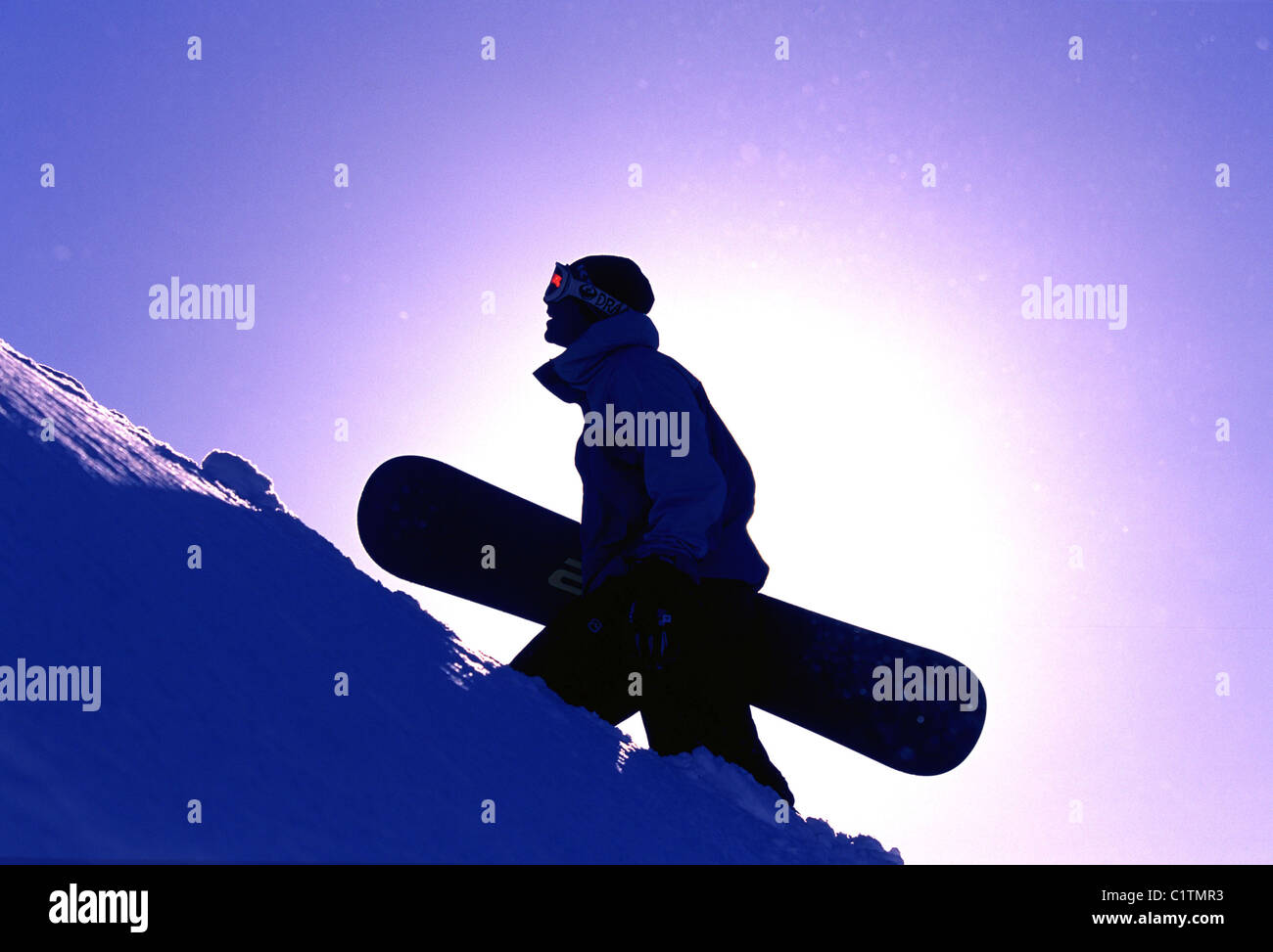 Person walking up hillside carrying snowboard Stock Photo - Alamy