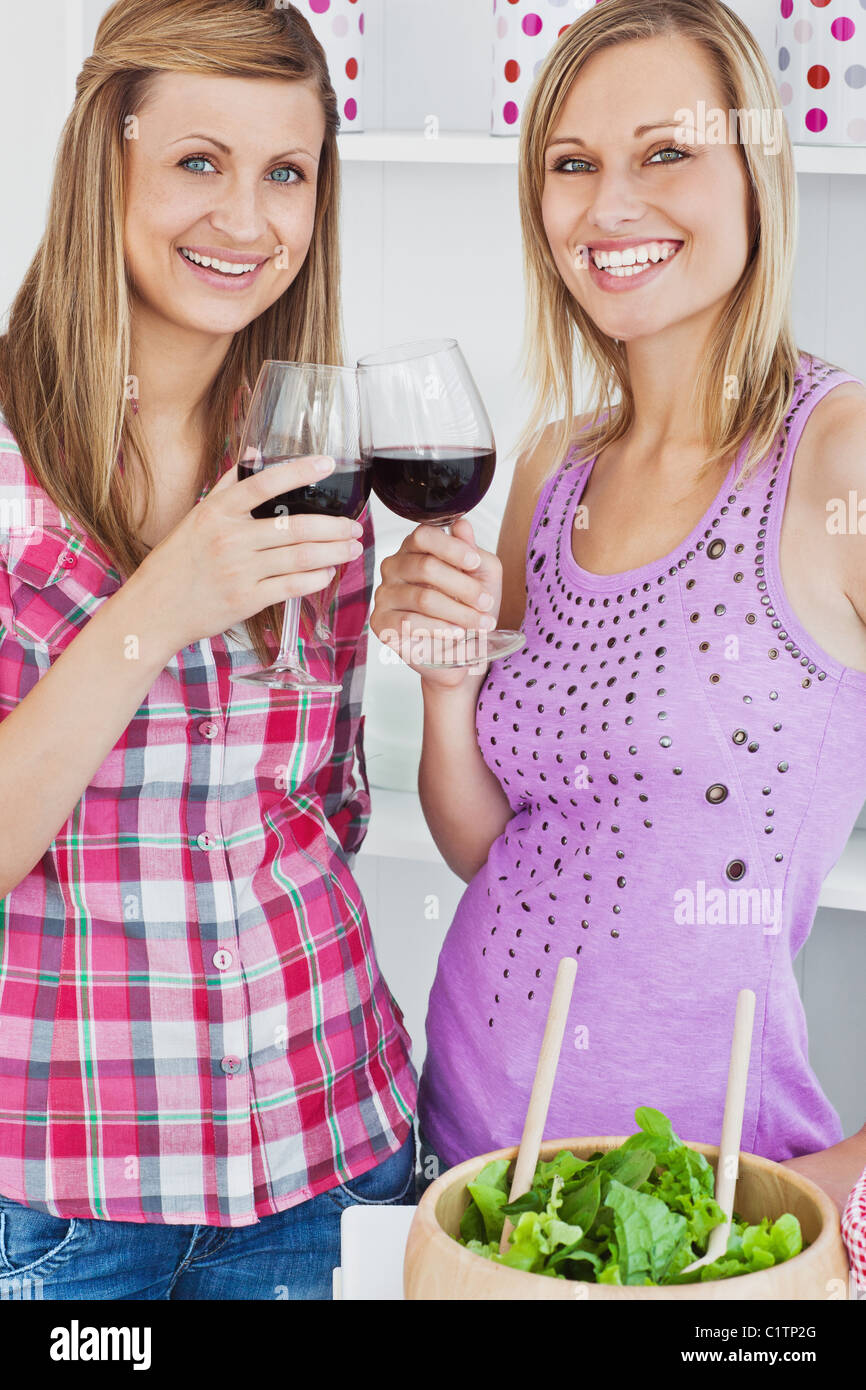 Two radiant women drinking wine after cooking in the kitchen Stock ...