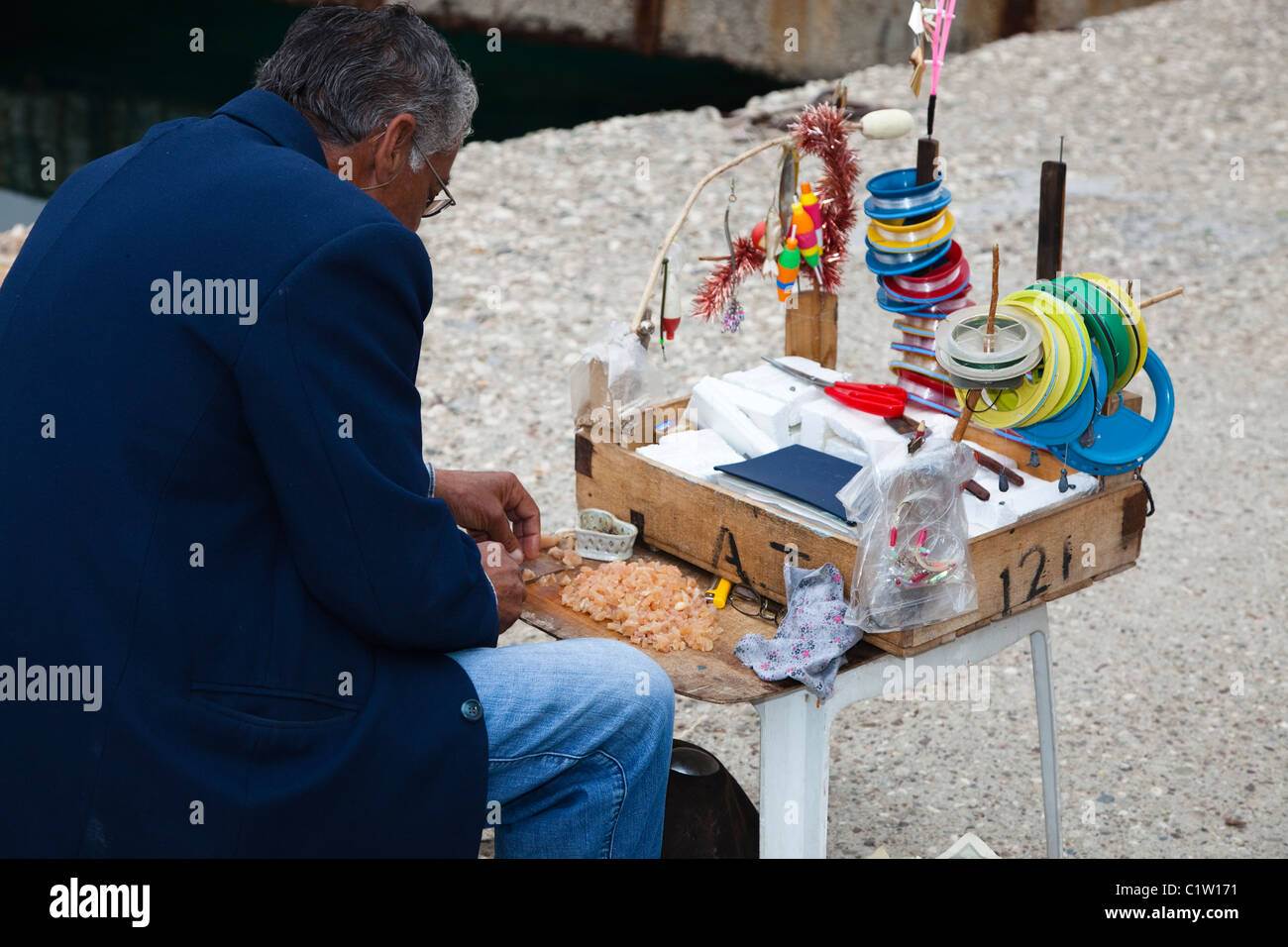 Turkish man preparing fishing bait on the quayside at Antalya harbour ...