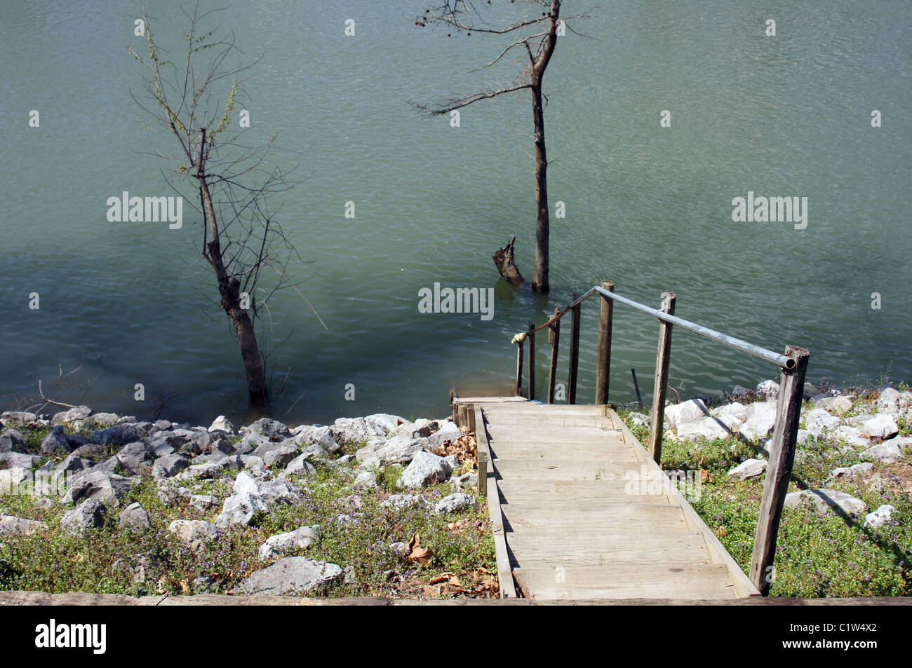 a photo of wooden steps with a railing leading down a river bank to the ...