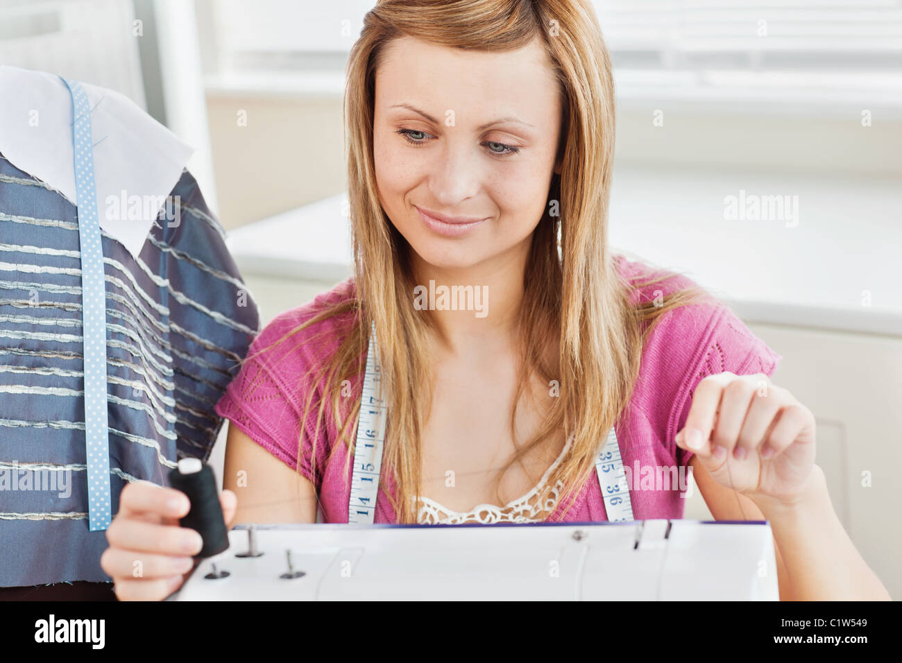 Concentrated young woman sewing clothes at home Stock Photo - Alamy