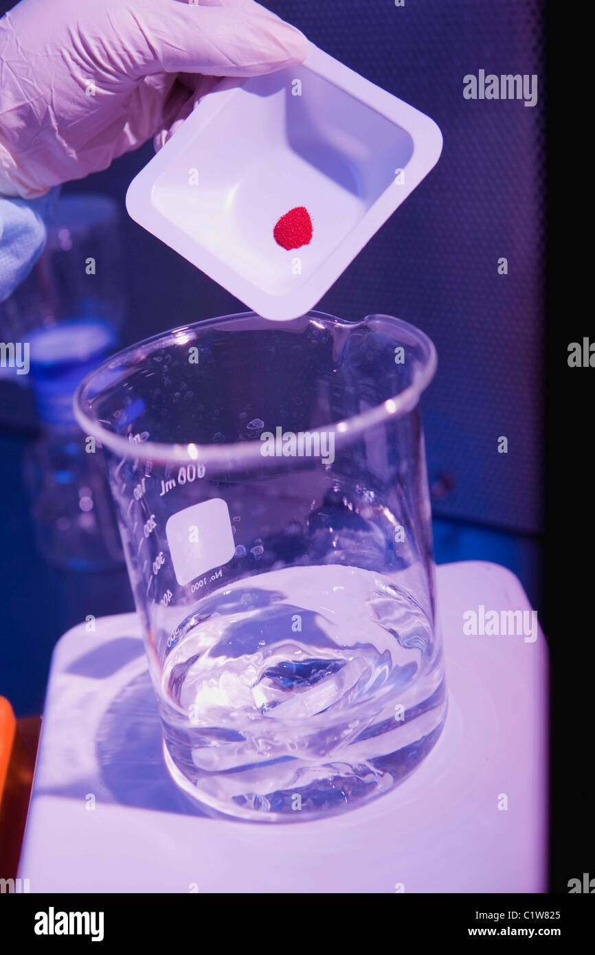 Scientist pouring substance into a beaker Stock Photo - Alamy
