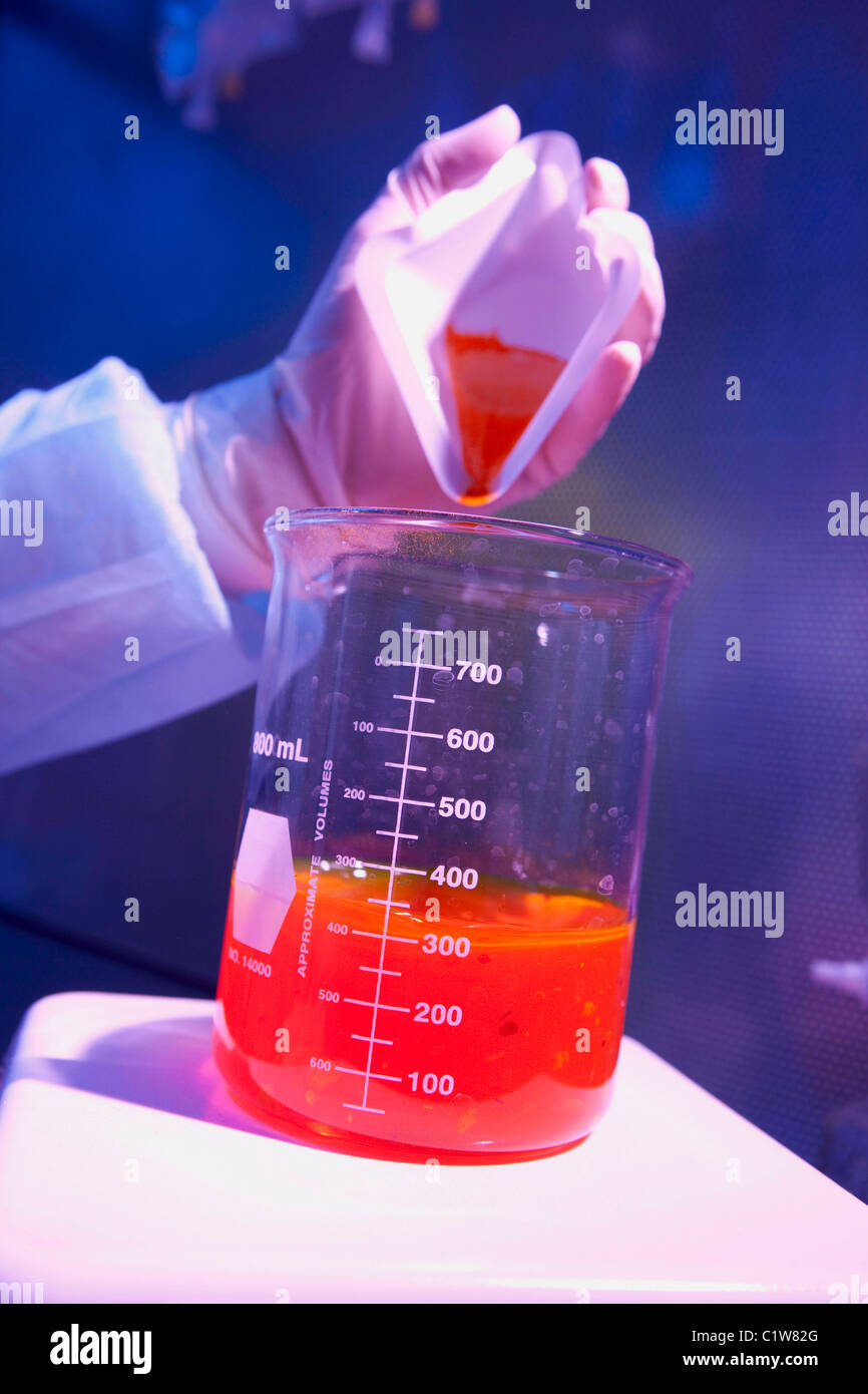 Scientist pouring substance into a beaker Stock Photo - Alamy