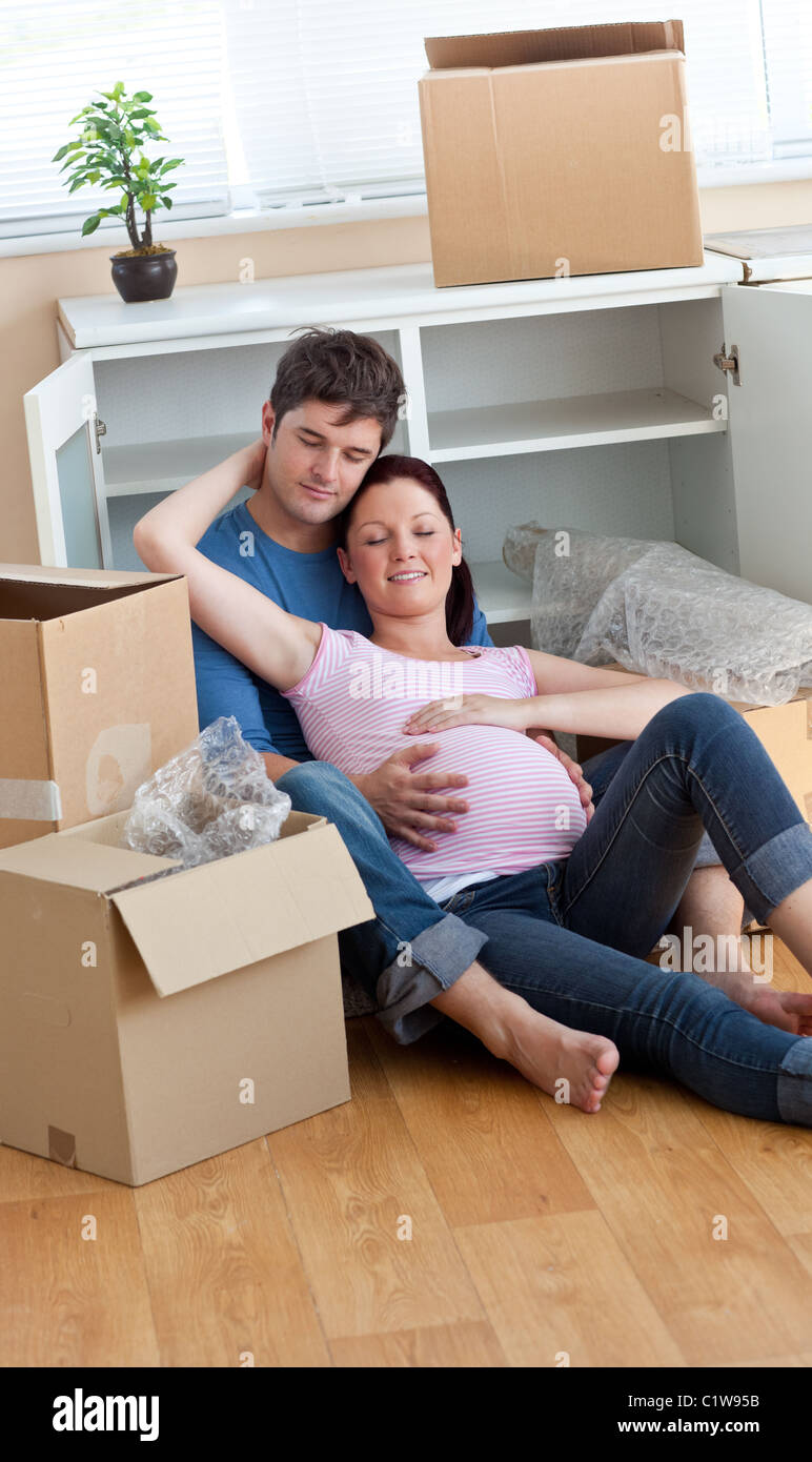 Future parents relaxing on the floor during a break after unpacking ...