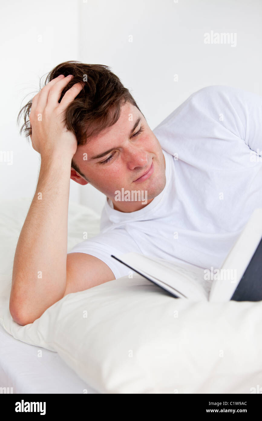 Young man reading a book lying on his bed Stock Photo - Alamy