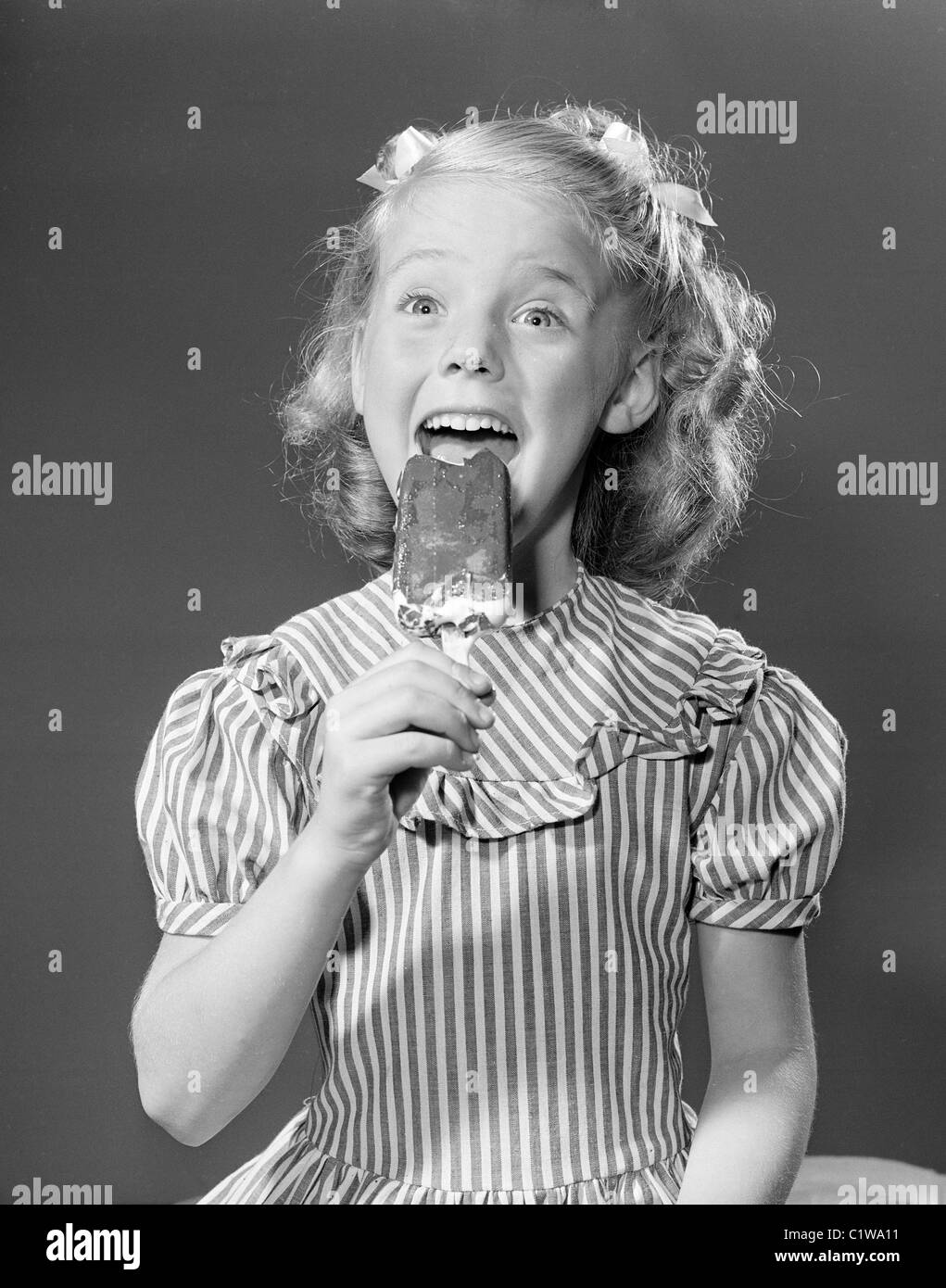 Studio portrait of girl eating popsicle Stock Photo - Alamy