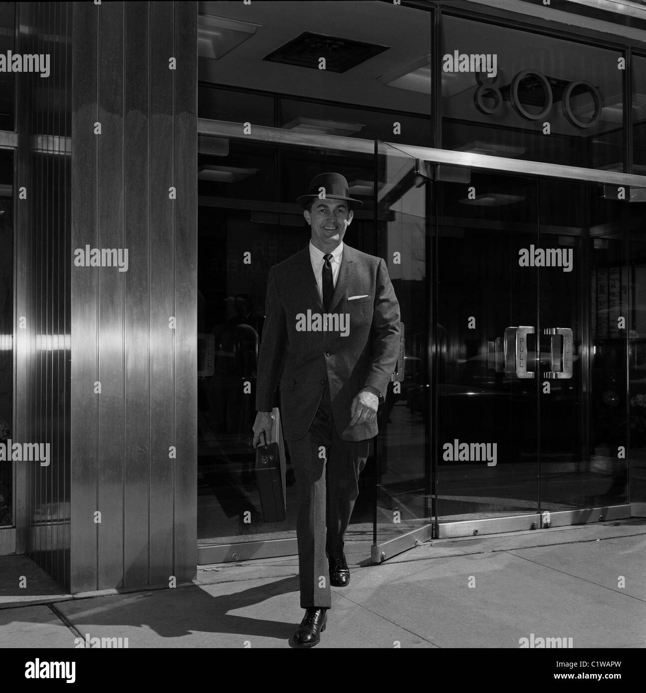 Businessman walking out of office building Stock Photo - Alamy