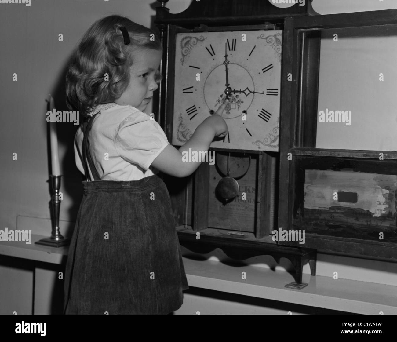 Girl adjusting clock Stock Photo - Alamy