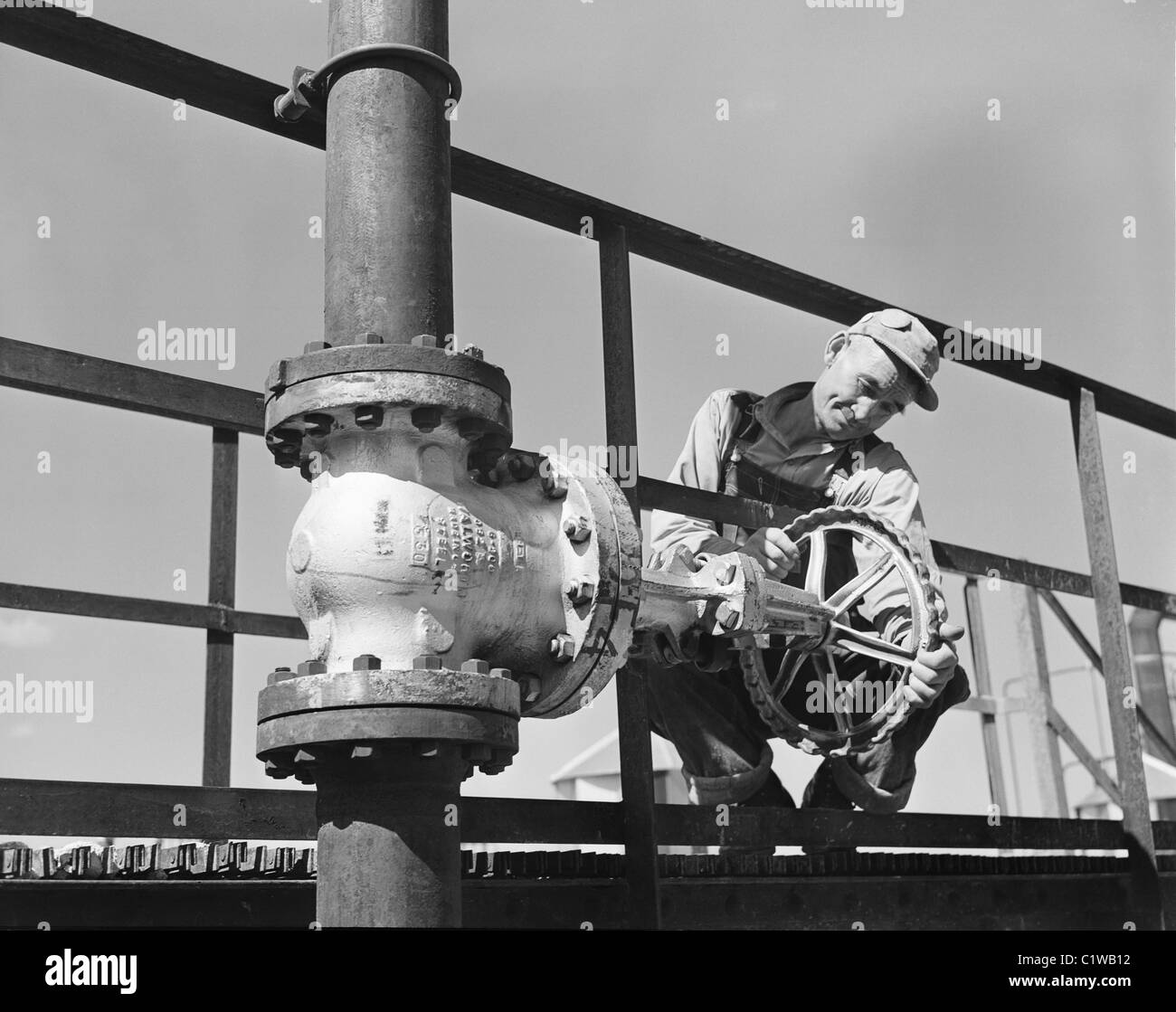 Worker adjusting valve on pipeline Stock Photo - Alamy