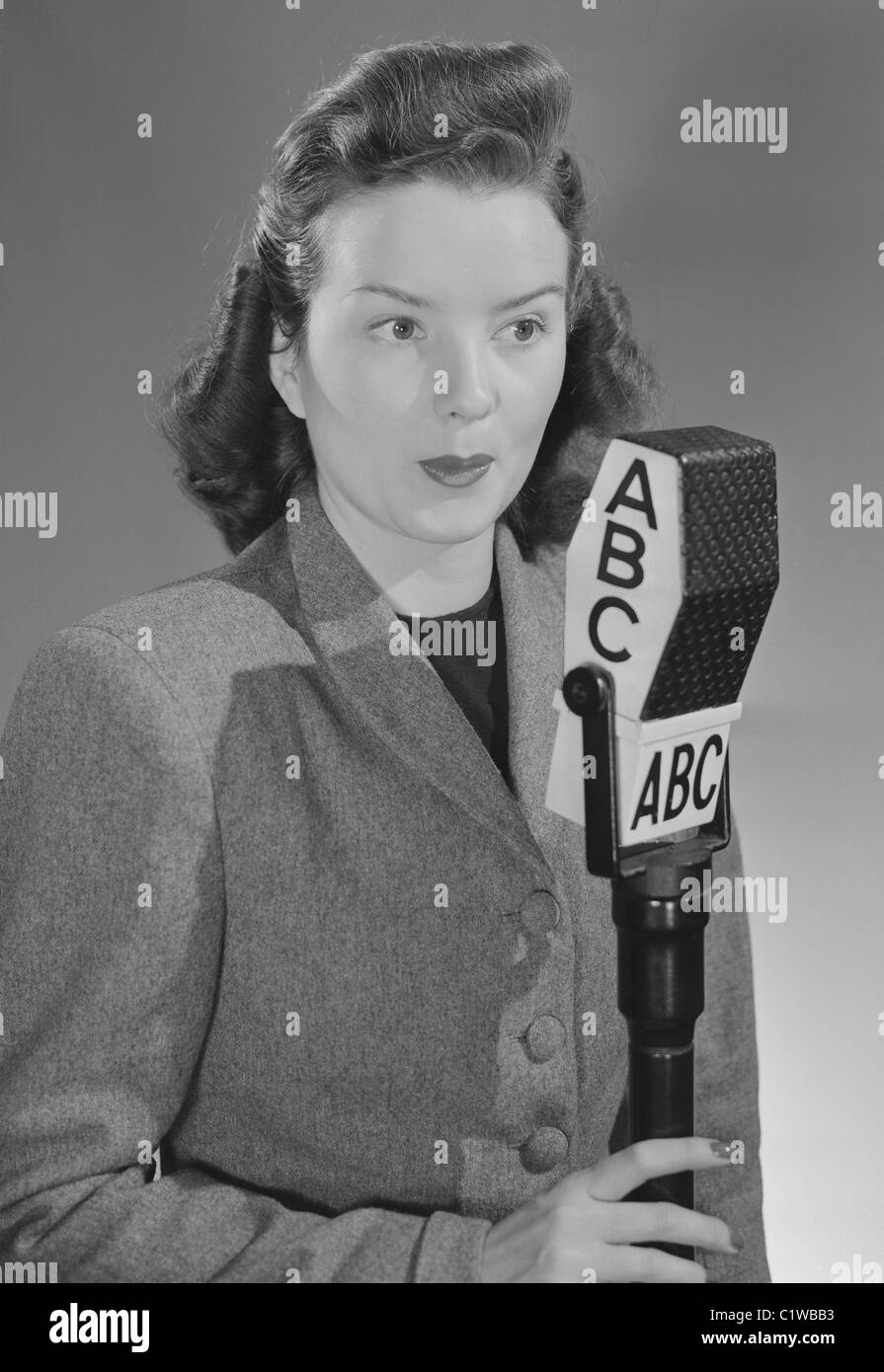 Studio portrait of female reporter speaking into microphone Stock Photo ...