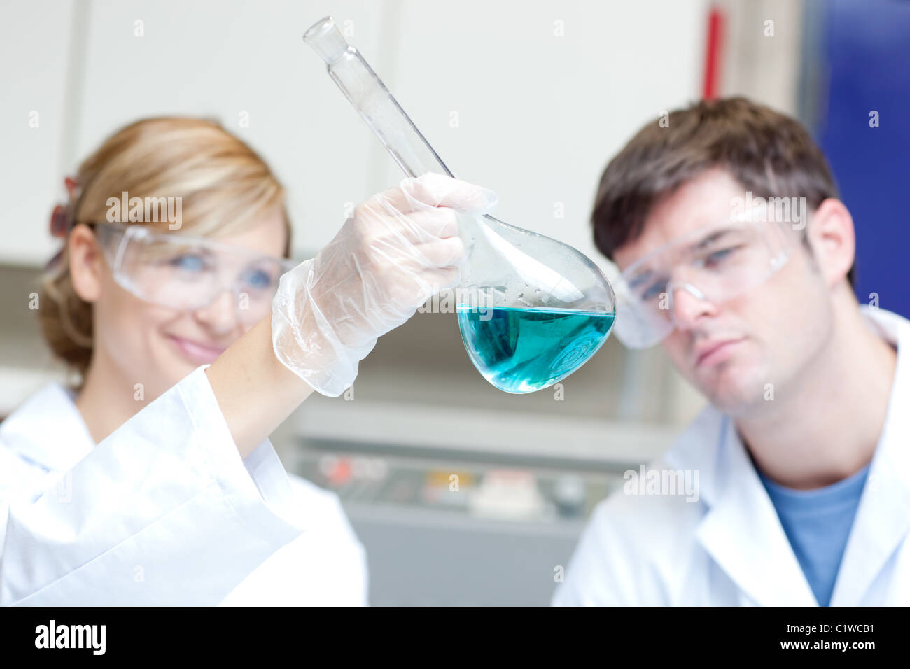 Two serious scientists looking at a blue liquid Stock Photo - Alamy