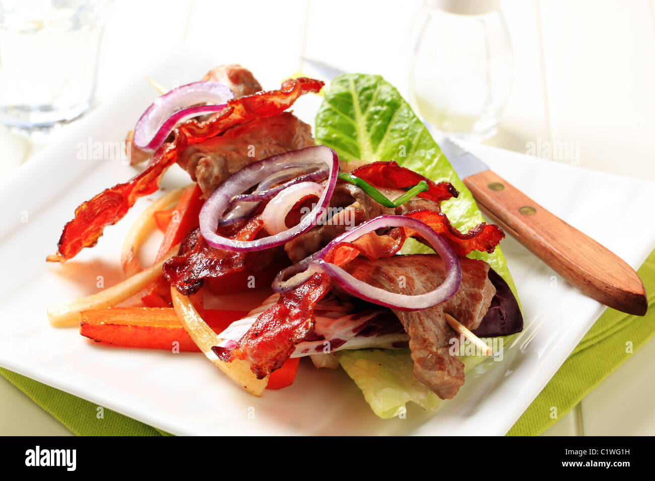 Shish kebab with crispy rashers of bacon and roasted vegetables Stock ...