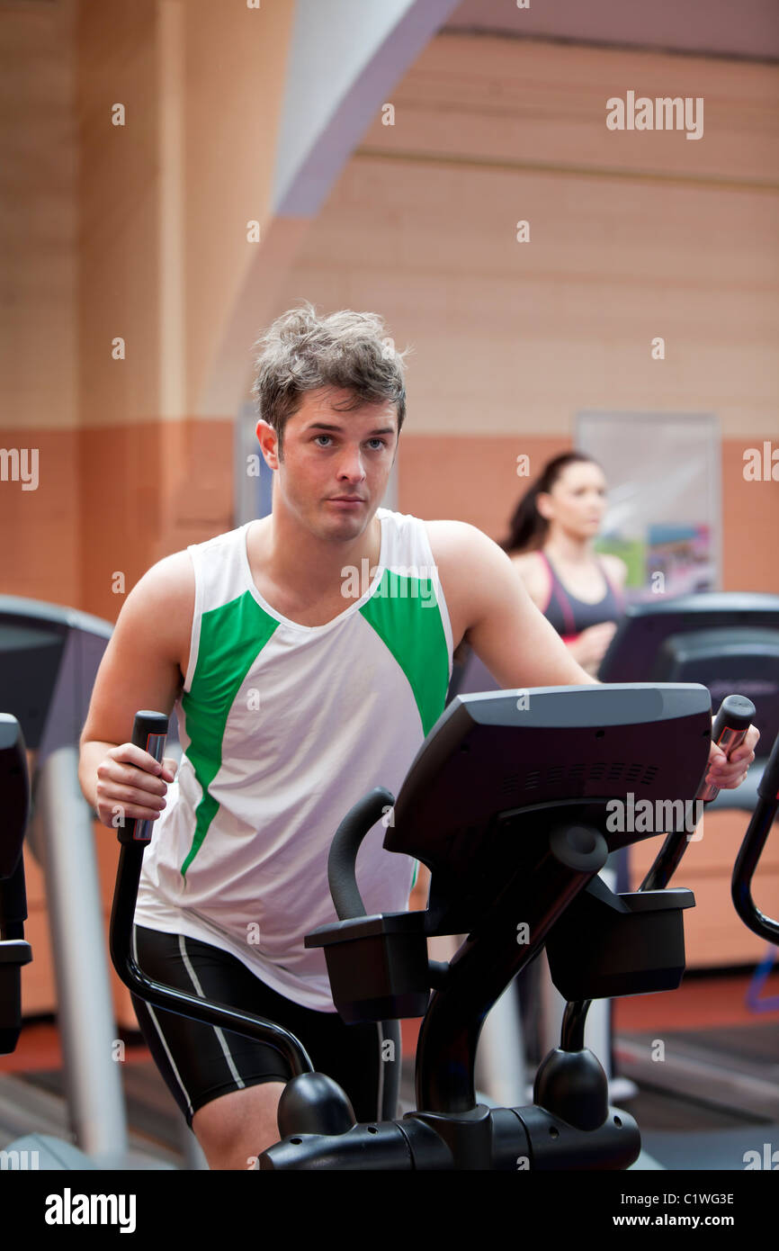 Handsome man doing exercises using cross trainer in a fitness centre ...